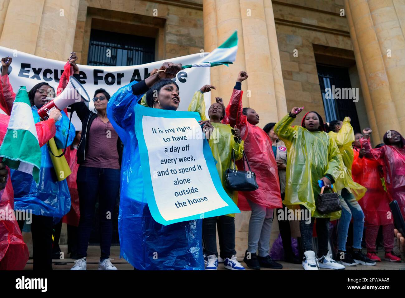 Domestic workers chant slogans as they hold placards during a protest ...
