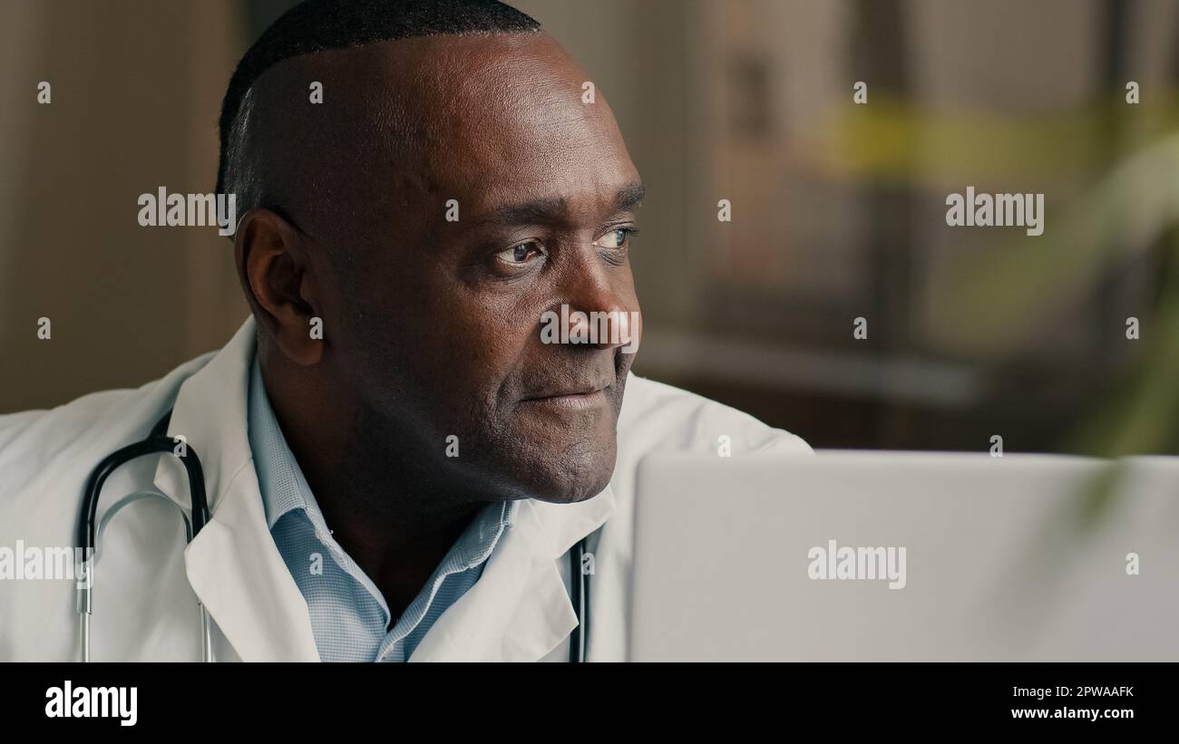 Happy middle-aged man doctor positive medical worker sits at hospital ...