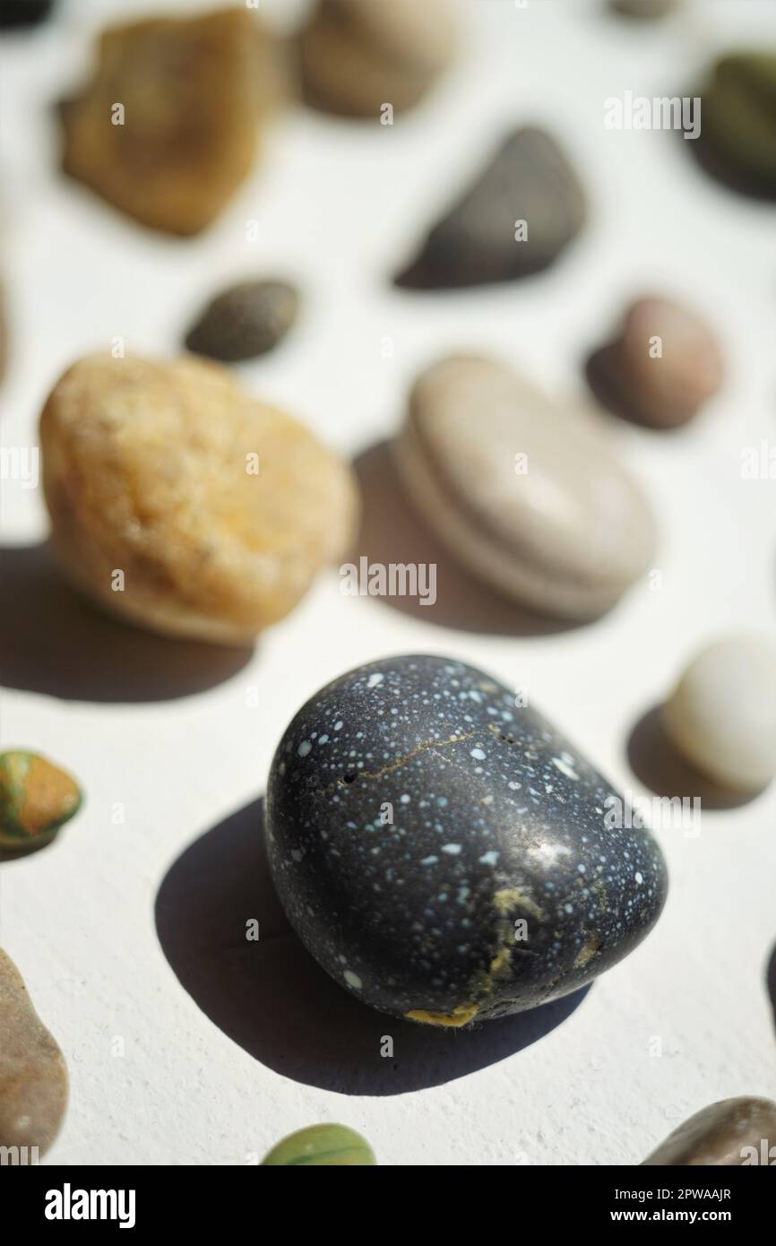 Closeup pebble stones with diferent shapes and colors on white surface ...
