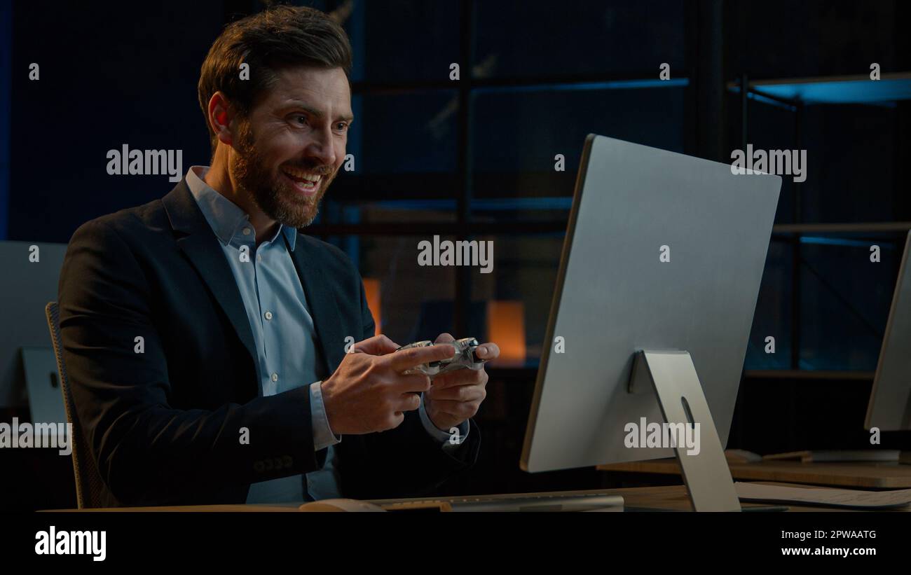 Adult businessman employee working in evening office happy male gamer ...