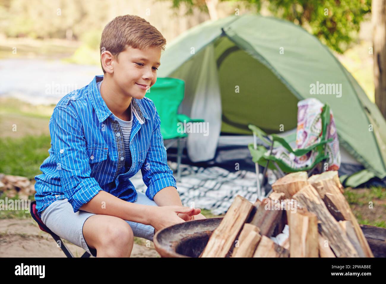 Waiting for someone to light the fire. a young boy sitting by an unlit ...