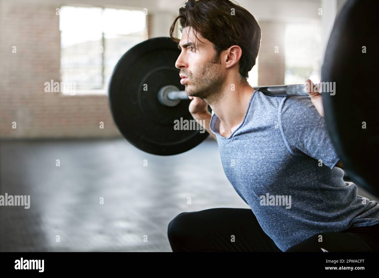Ready for the push. a young man working out with weights in the gym ...