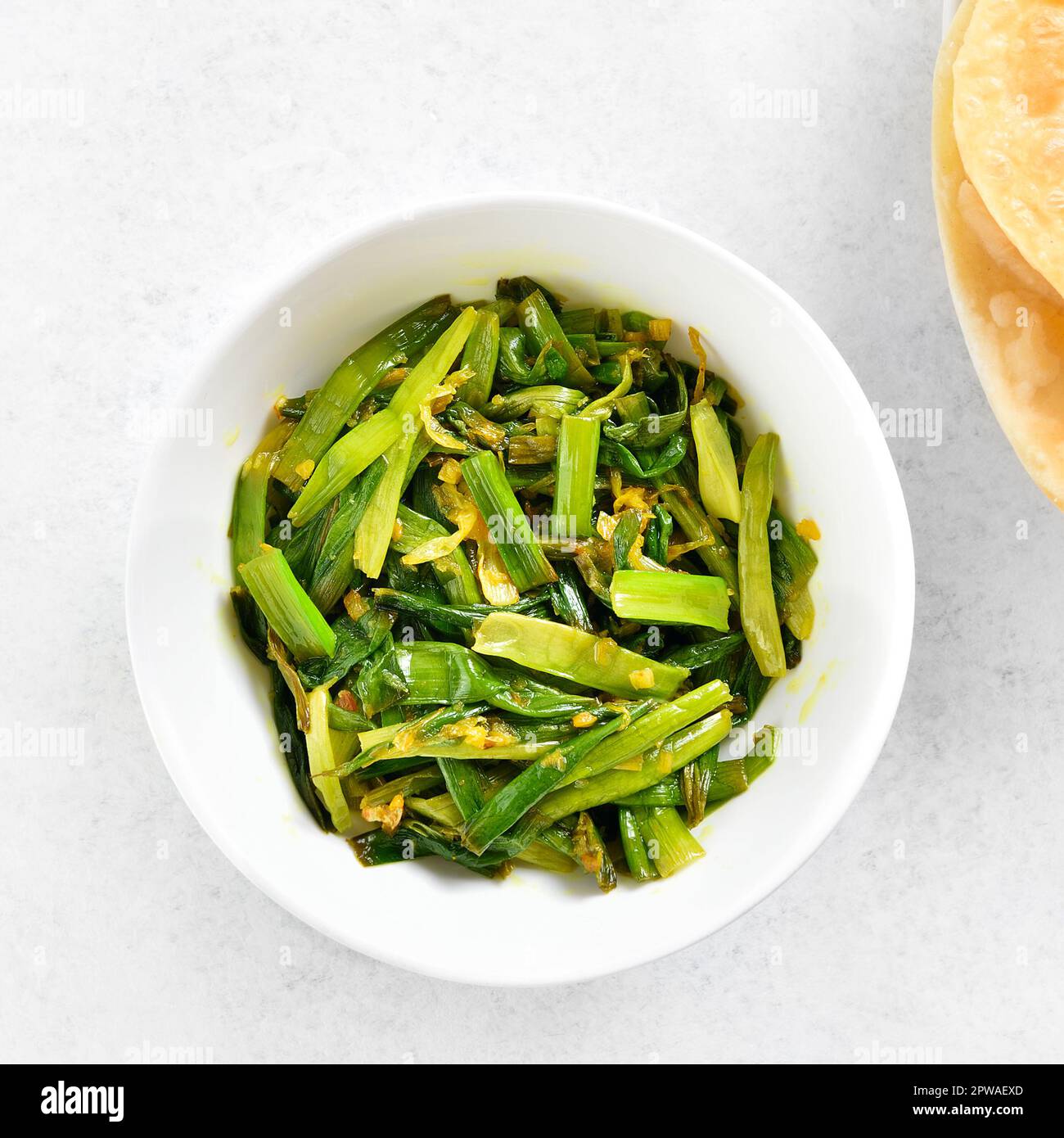 Indian style spring onion stir fry in bowl over white background. Top ...