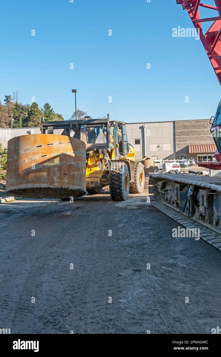 A large front-end loader carries a piece of equipment for creating ...