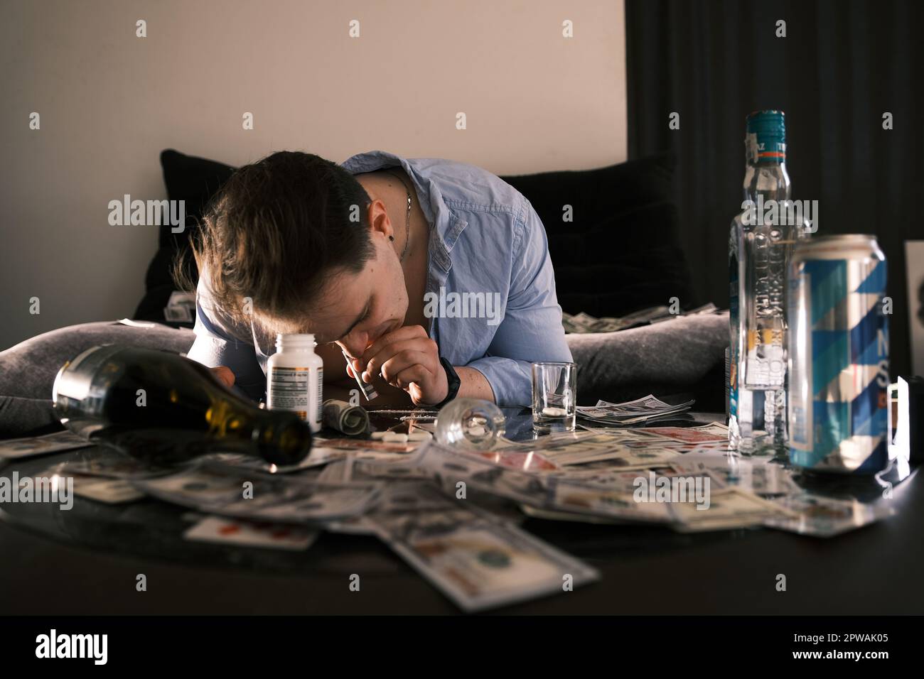 Young addicted junkie man sniffing snorting cocaine lines on mirror ...