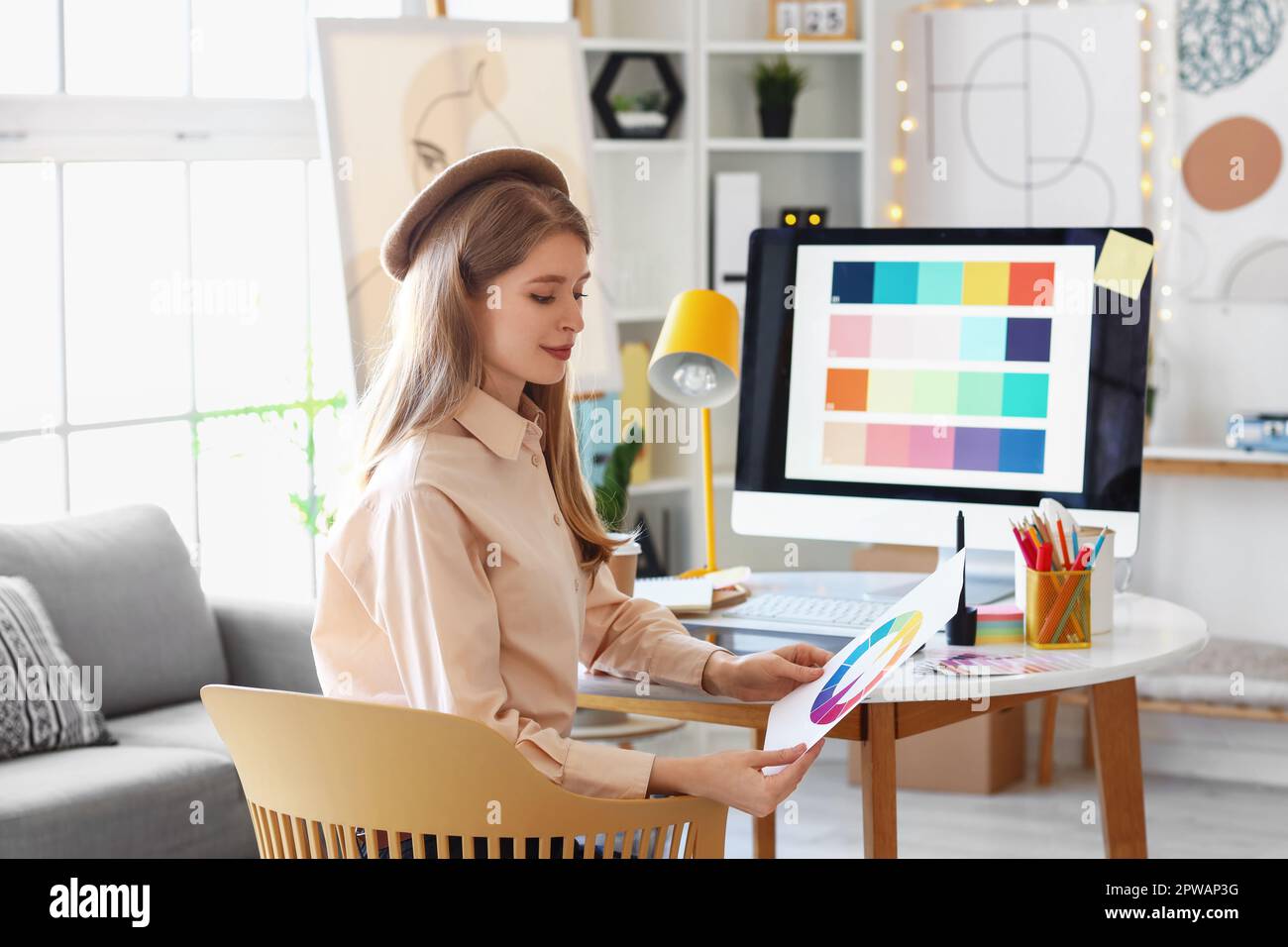Female graphic designer working with color palette at table in office ...