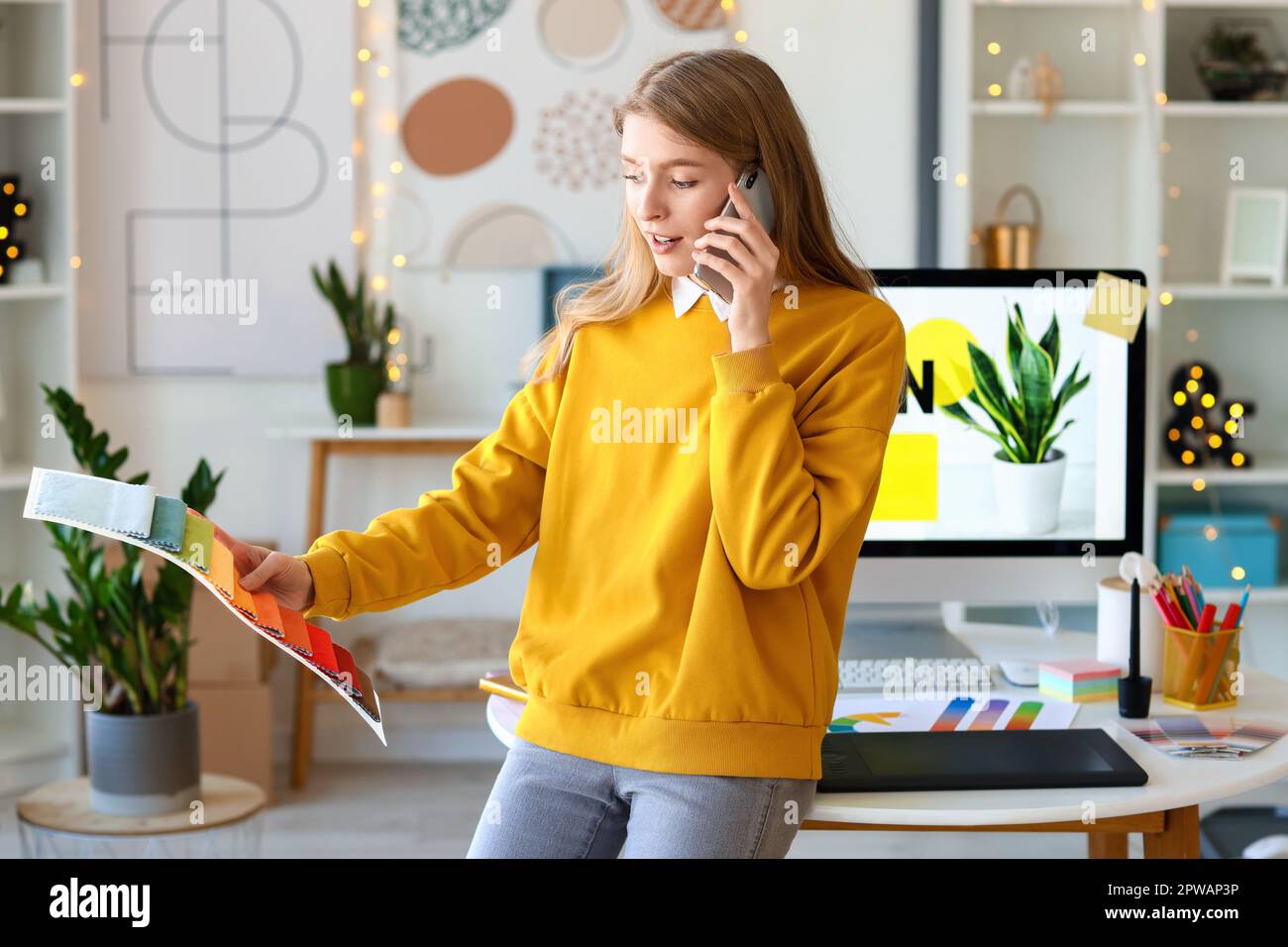 Female graphic designer with fabric samples talking by mobile phone in ...