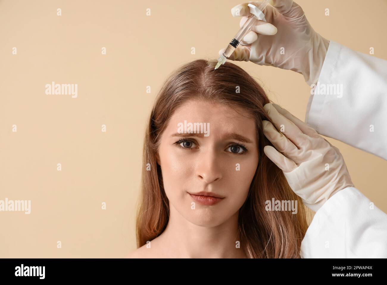 Young woman receiving injection for hair growth on beige background ...