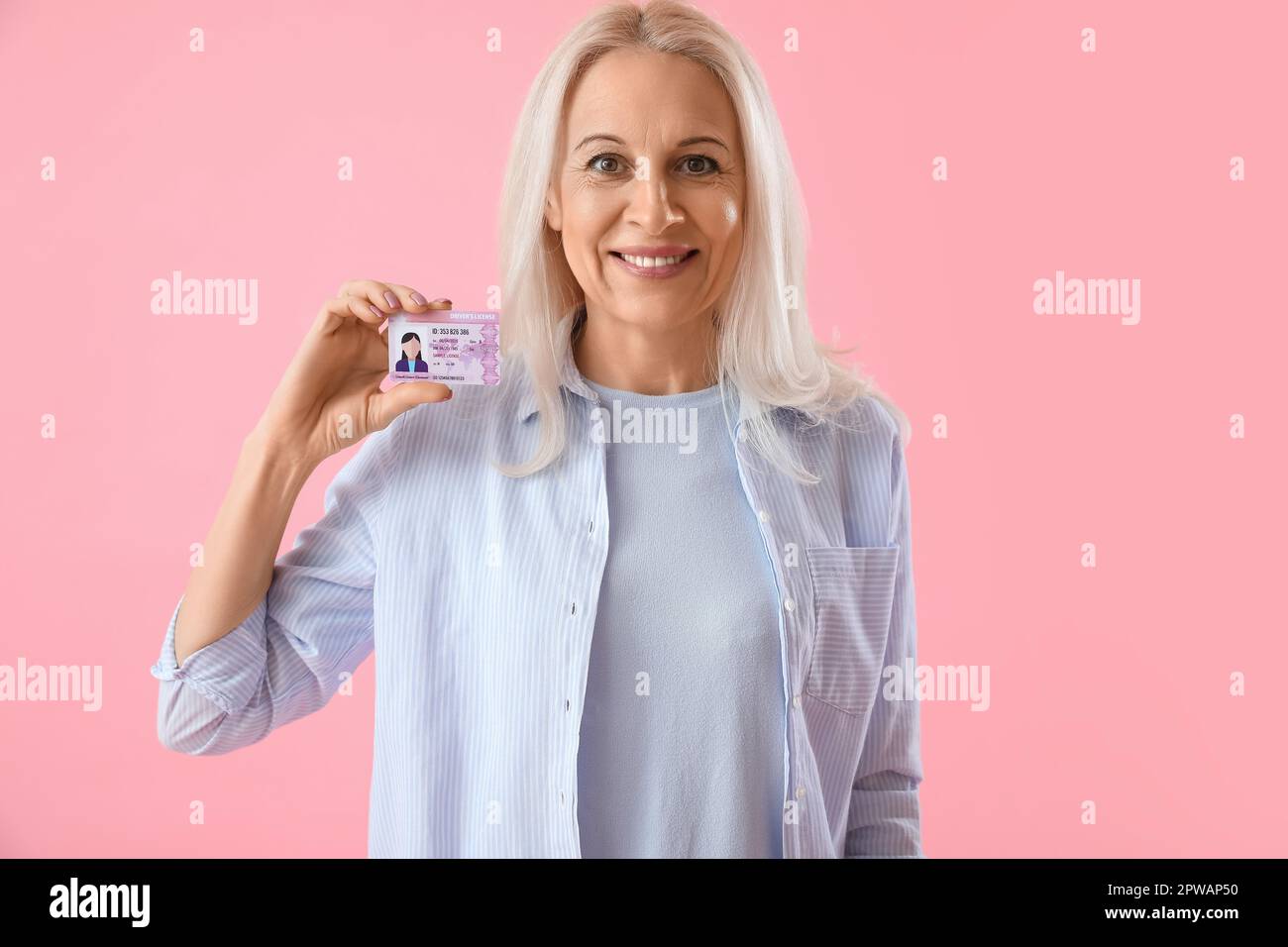 Mature woman with driving license on pink background Stock Photo - Alamy