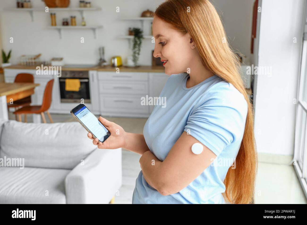 Woman with glucose sensor using mobile phone for measuring of blood ...
