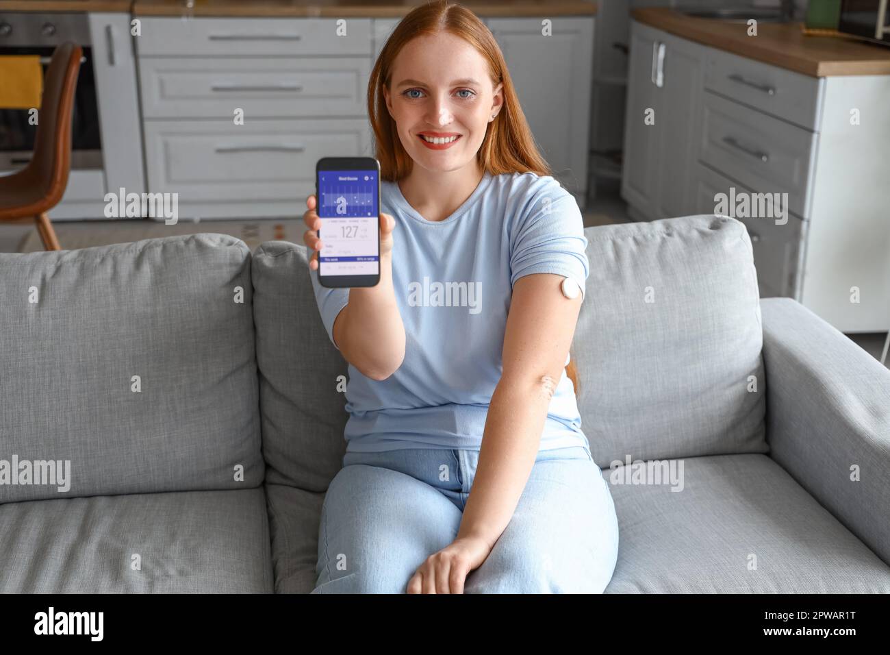 Woman with glucose sensor using mobile phone for measuring of blood ...