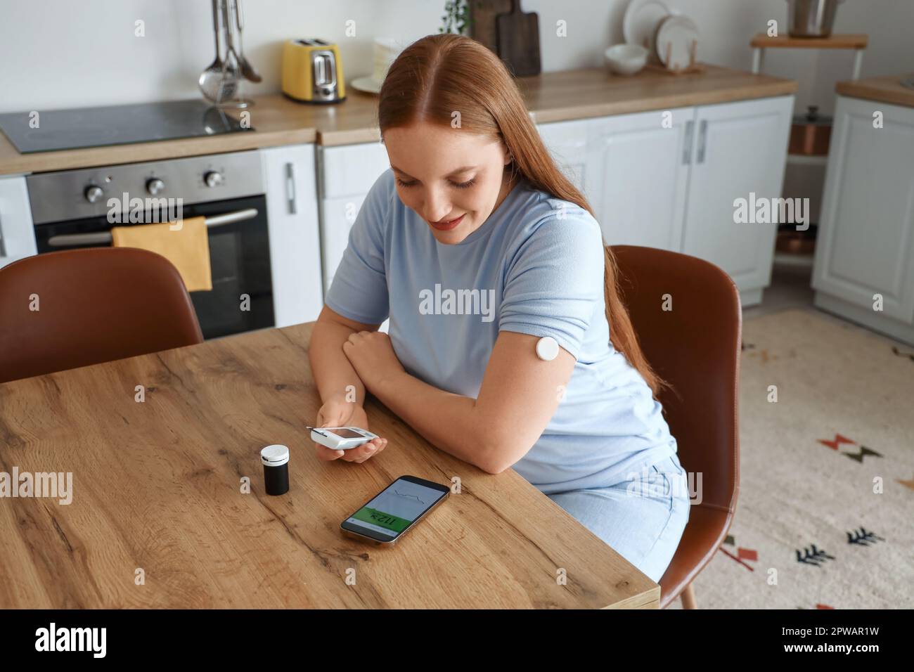 Woman with glucose sensor using mobile phone for measuring of blood ...