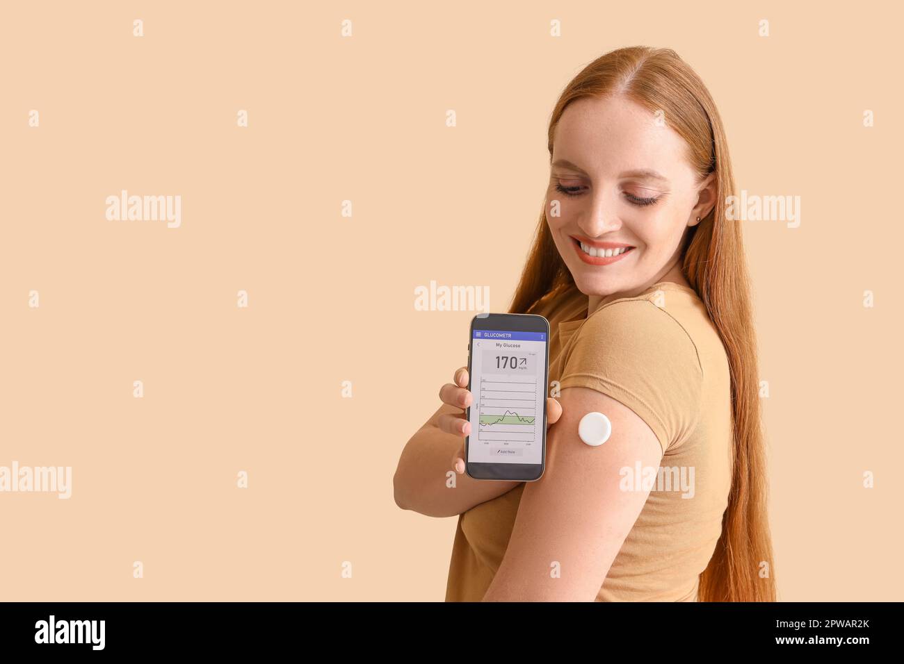 Woman with glucose sensor using mobile phone for measuring blood sugar ...