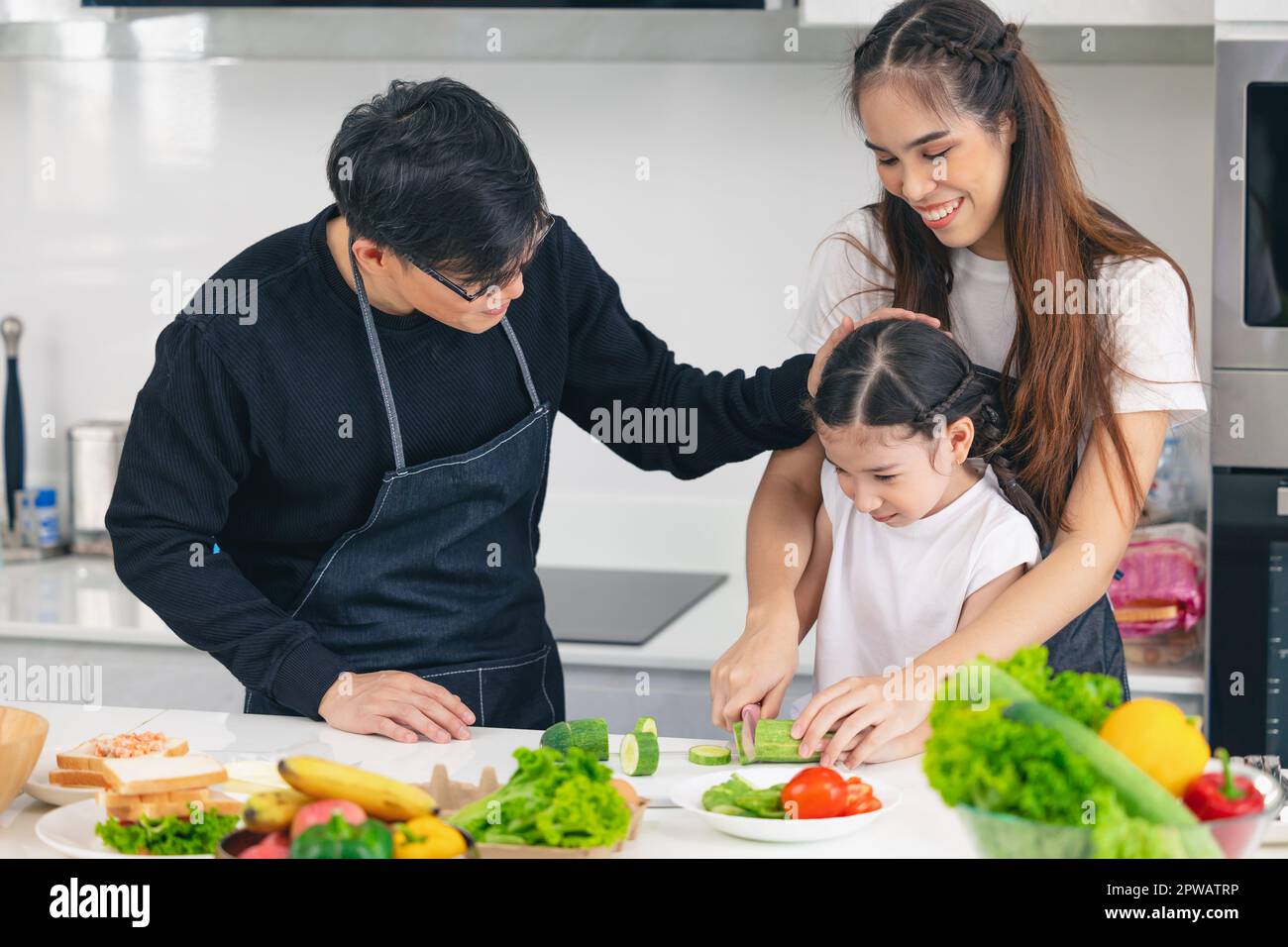 Asian Family people enjoy teaching children cook food using knife for ...