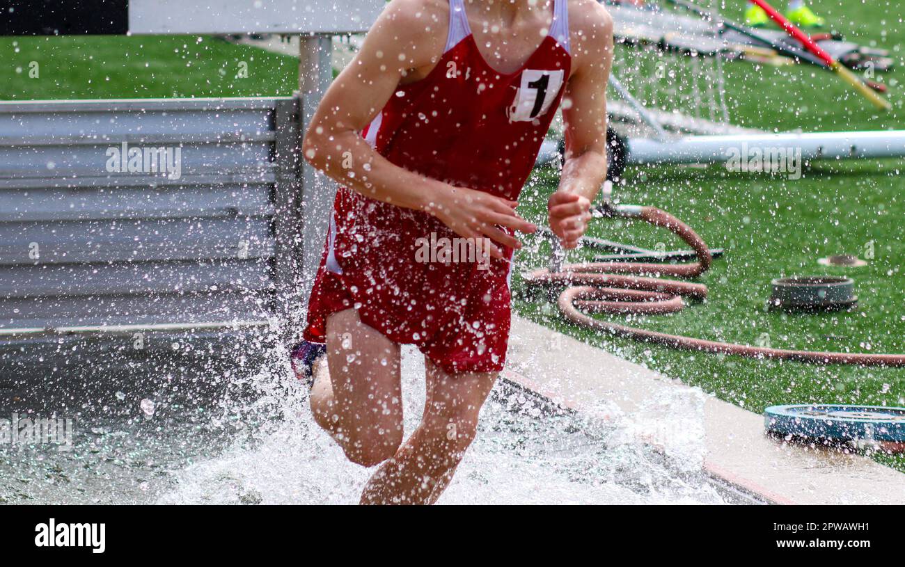 Front view of a young high school runner splashing in the water of the ...