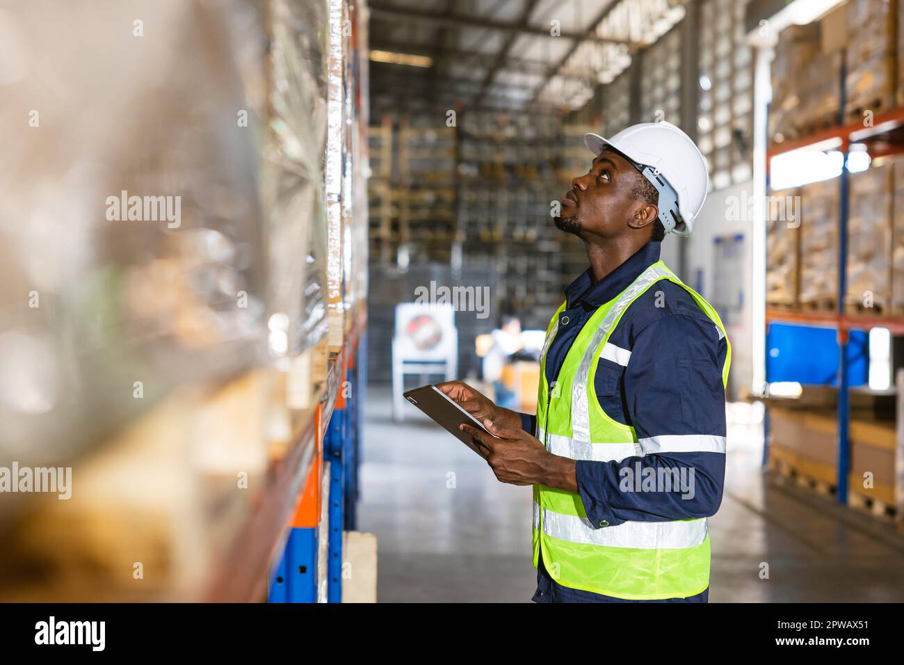 Photo of a male worker inspecting count products stock in a warehouse ...