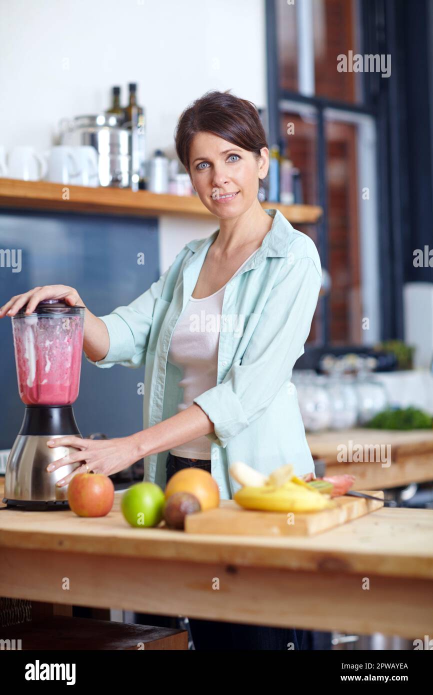 Making a healthy blend. an attractive woman making a fruit smoothie in ...