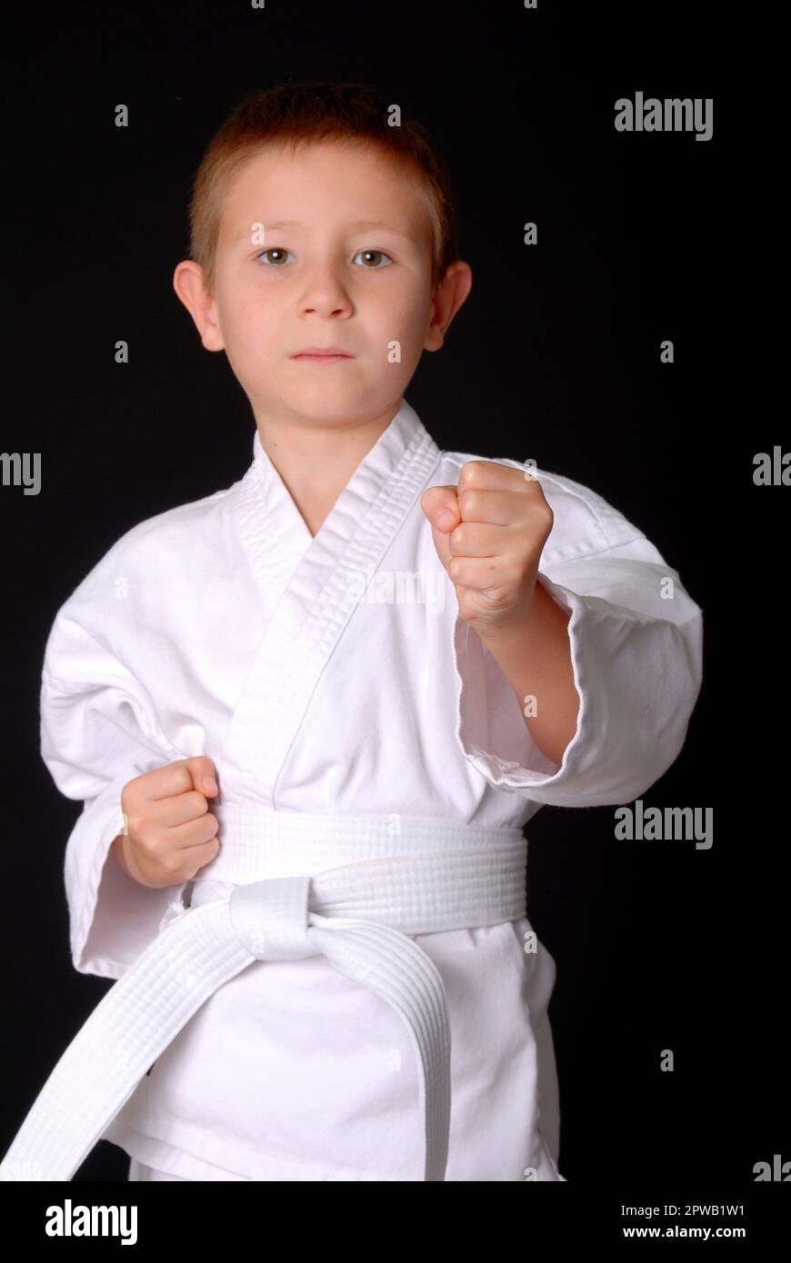 (Focus on fist) Young boy in karate outfit making fighting movement ...