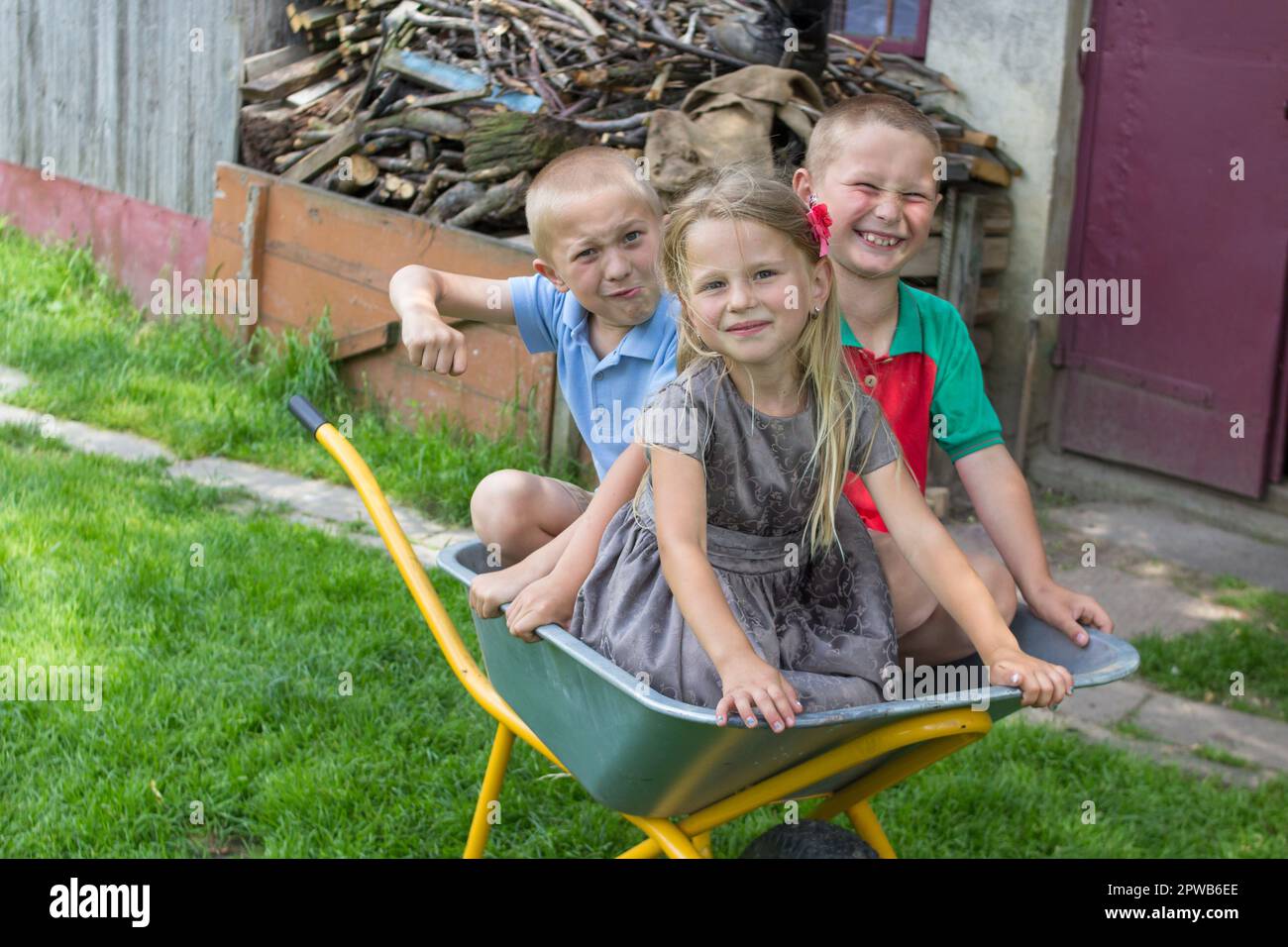 happy children sitting in a wheelbarrow, two boys and a girl Stock ...