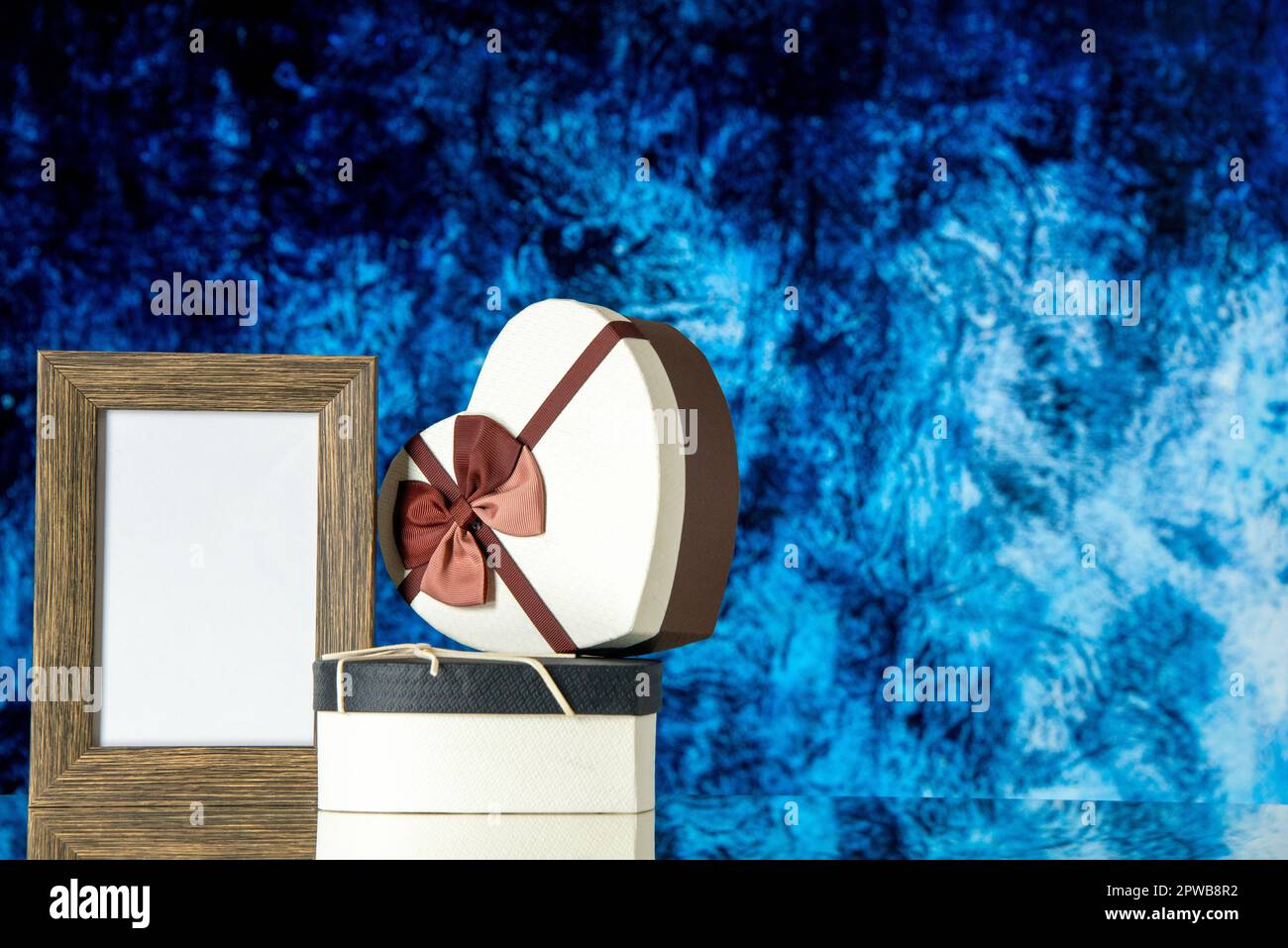 front view valentines day presents with empty picture frame on a blue ...