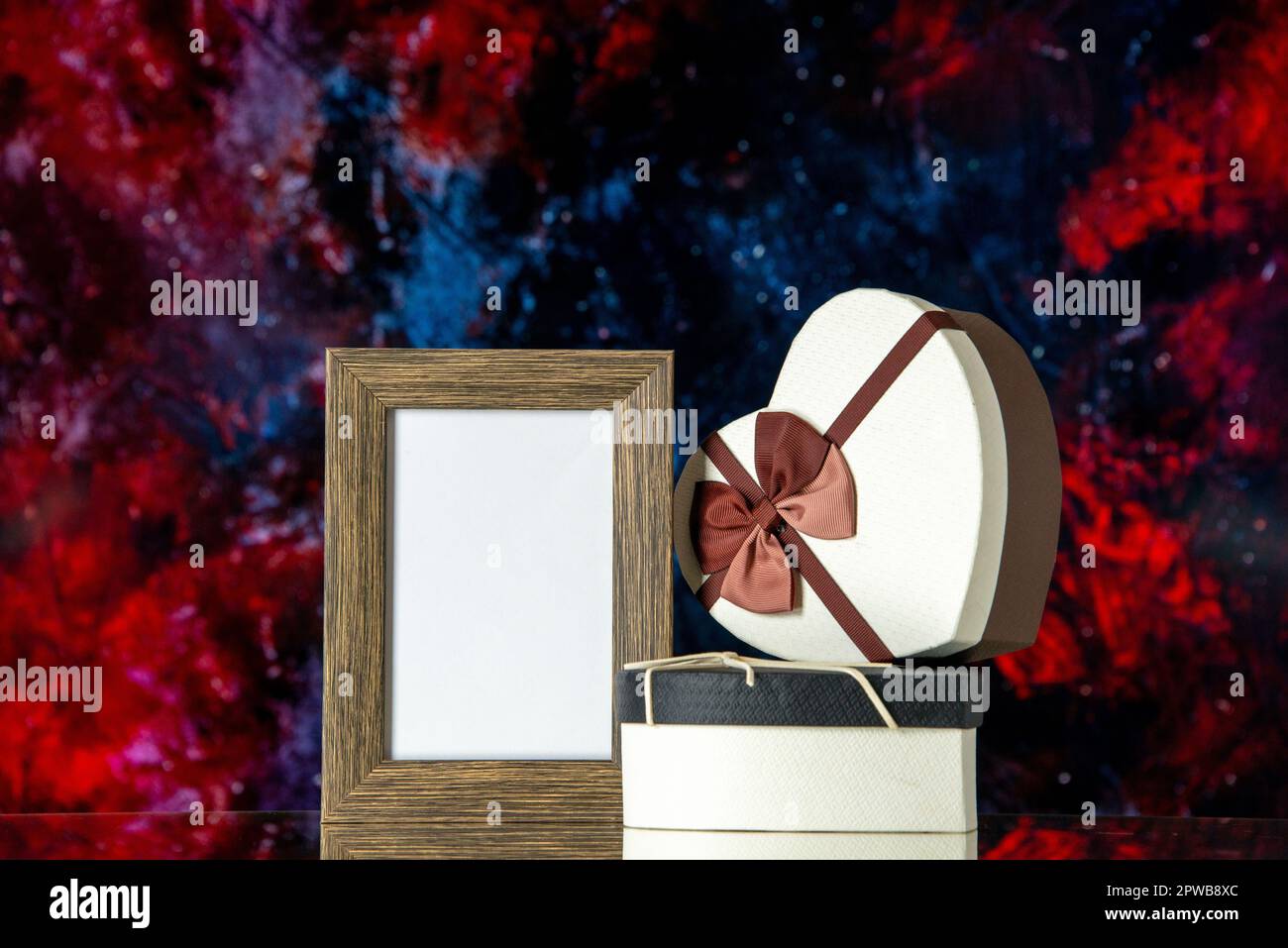 front view valentines day presents with empty picture frame on dark ...