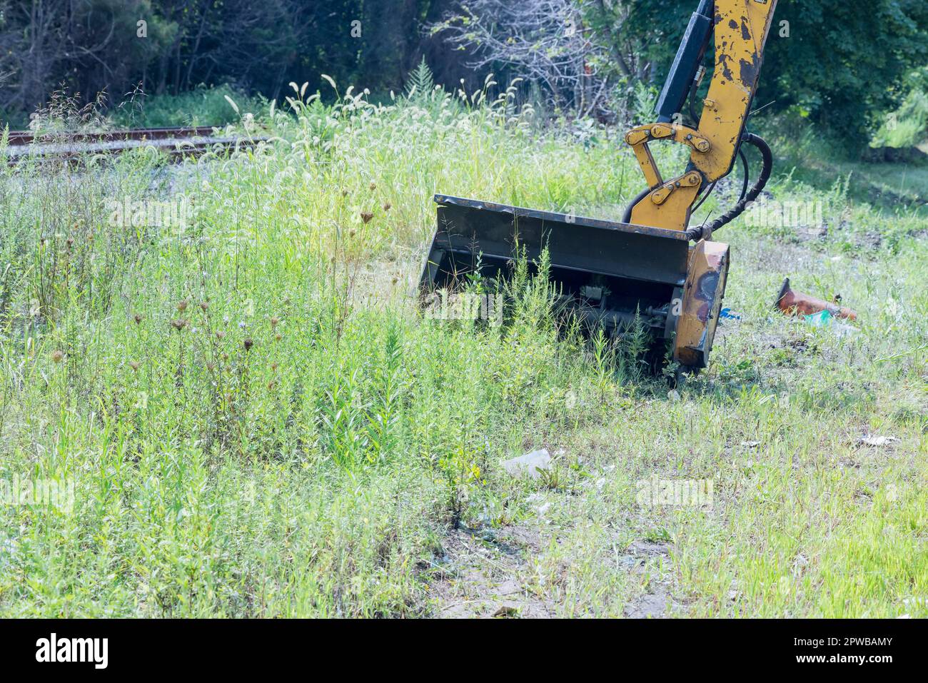 There is utility worker on side of road mowing tall grass in front his ...