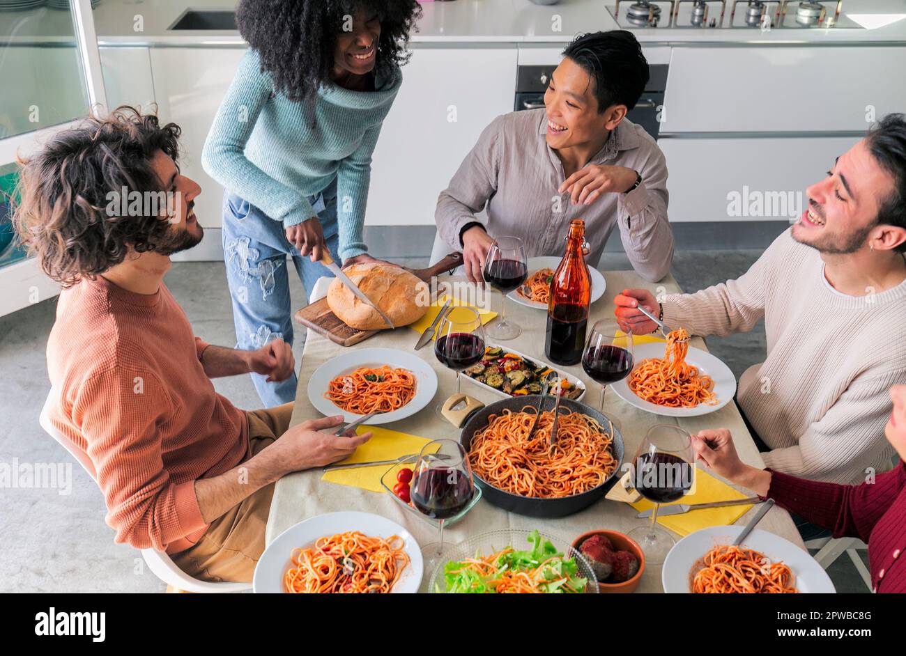 black girl cutting bread - Smiling friends are having a lunch party at ...
