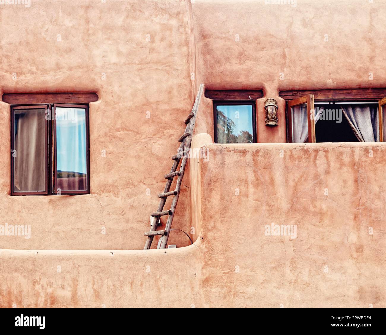A horizontal, minimalist image of an adobe building with a wooden ...