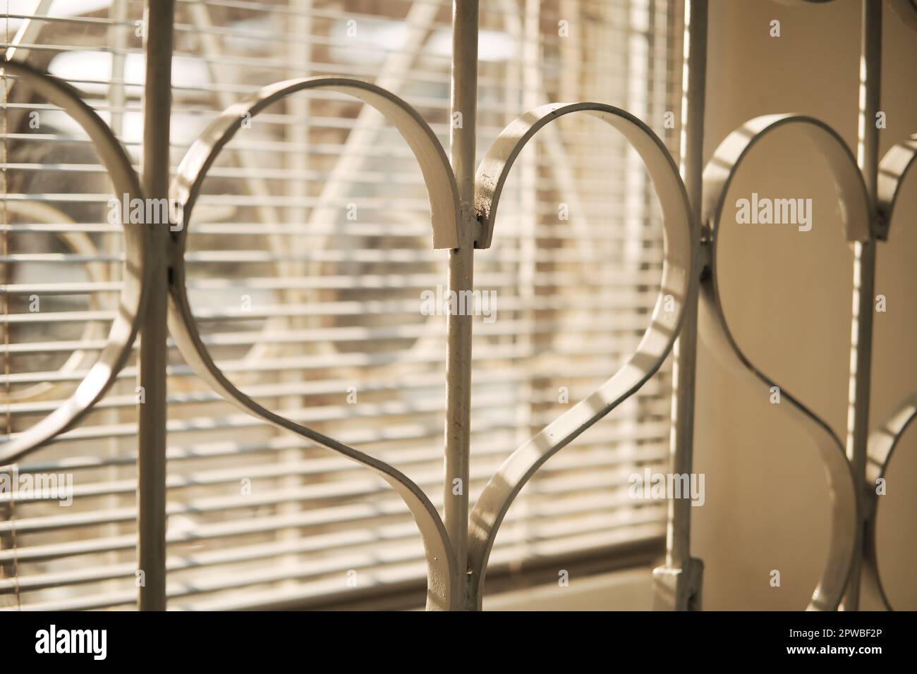 Window with a decorative lattice with patterns in evening sun. Heart ...