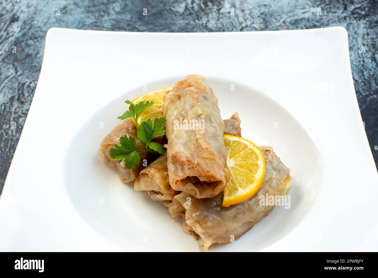front view delicious cabbage dolma with lemon inside plate on dark ...