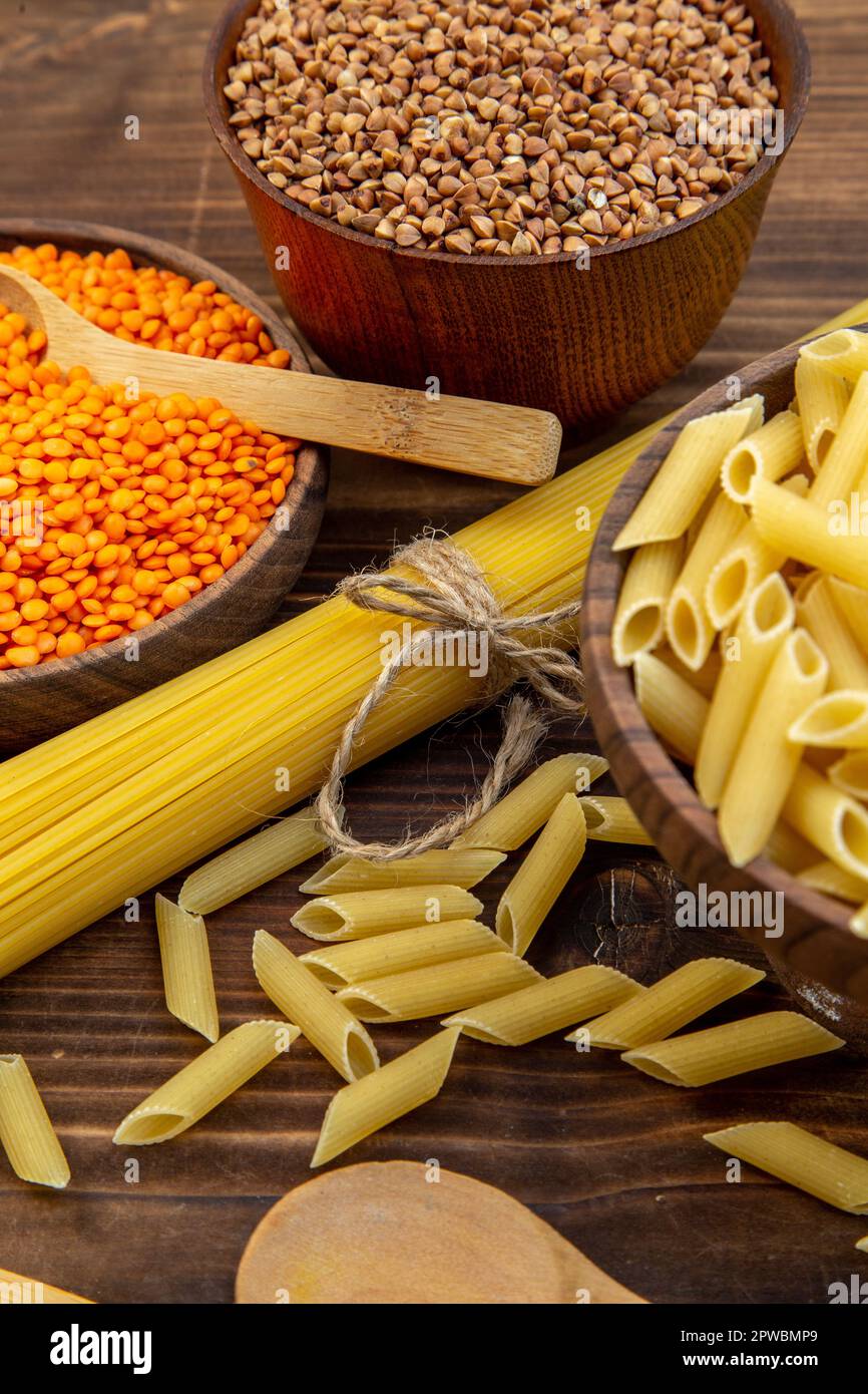 front view raw pasta with buckwheat and lentils on brown background ...