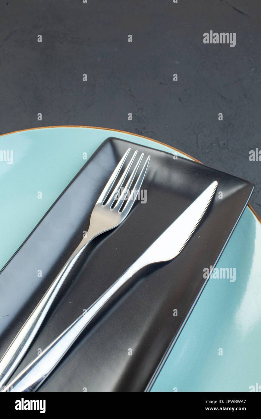front view long black plate with blue plate fork and knife on dark ...