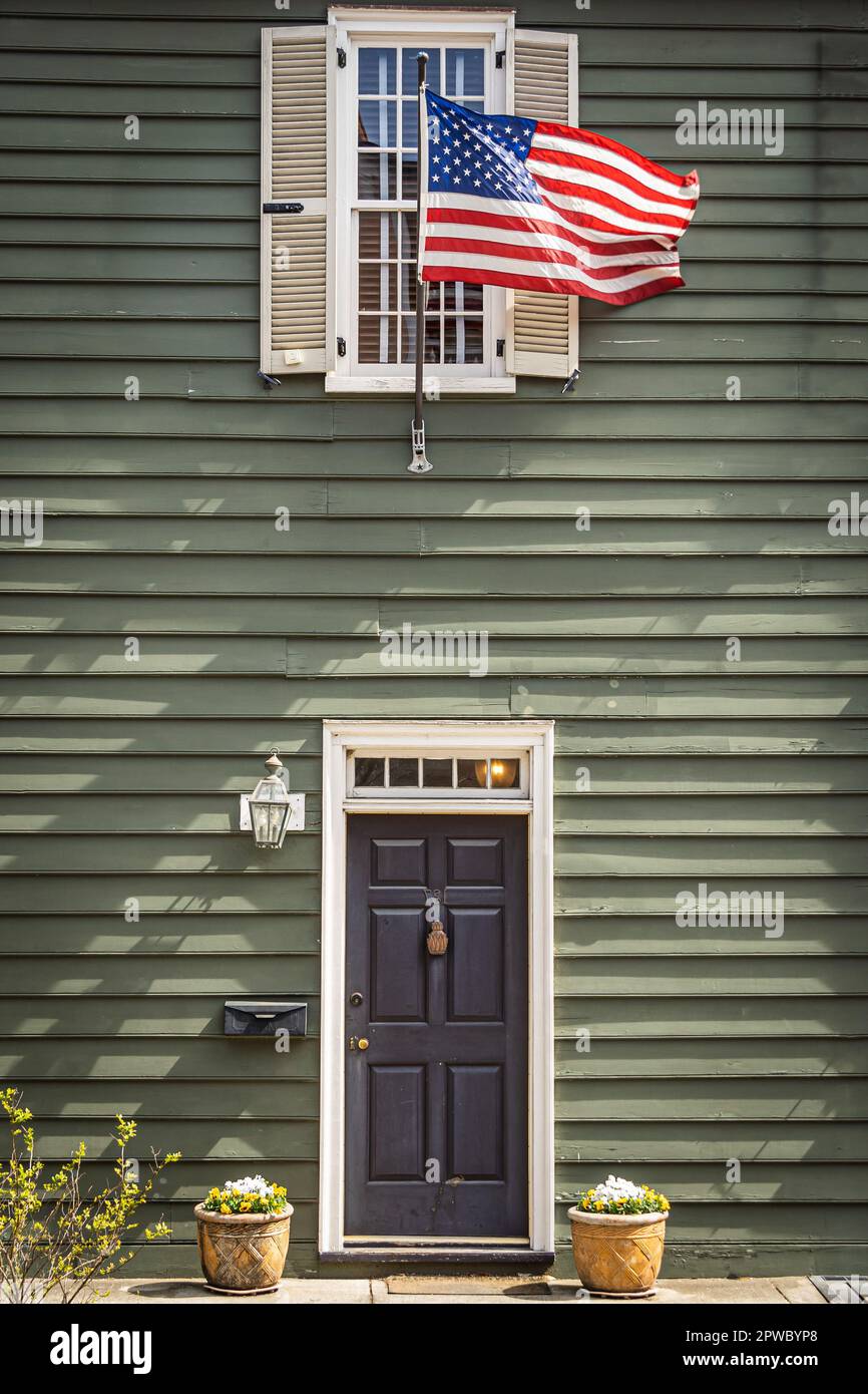 An American flag hung above the door of a colonial style home painted ...