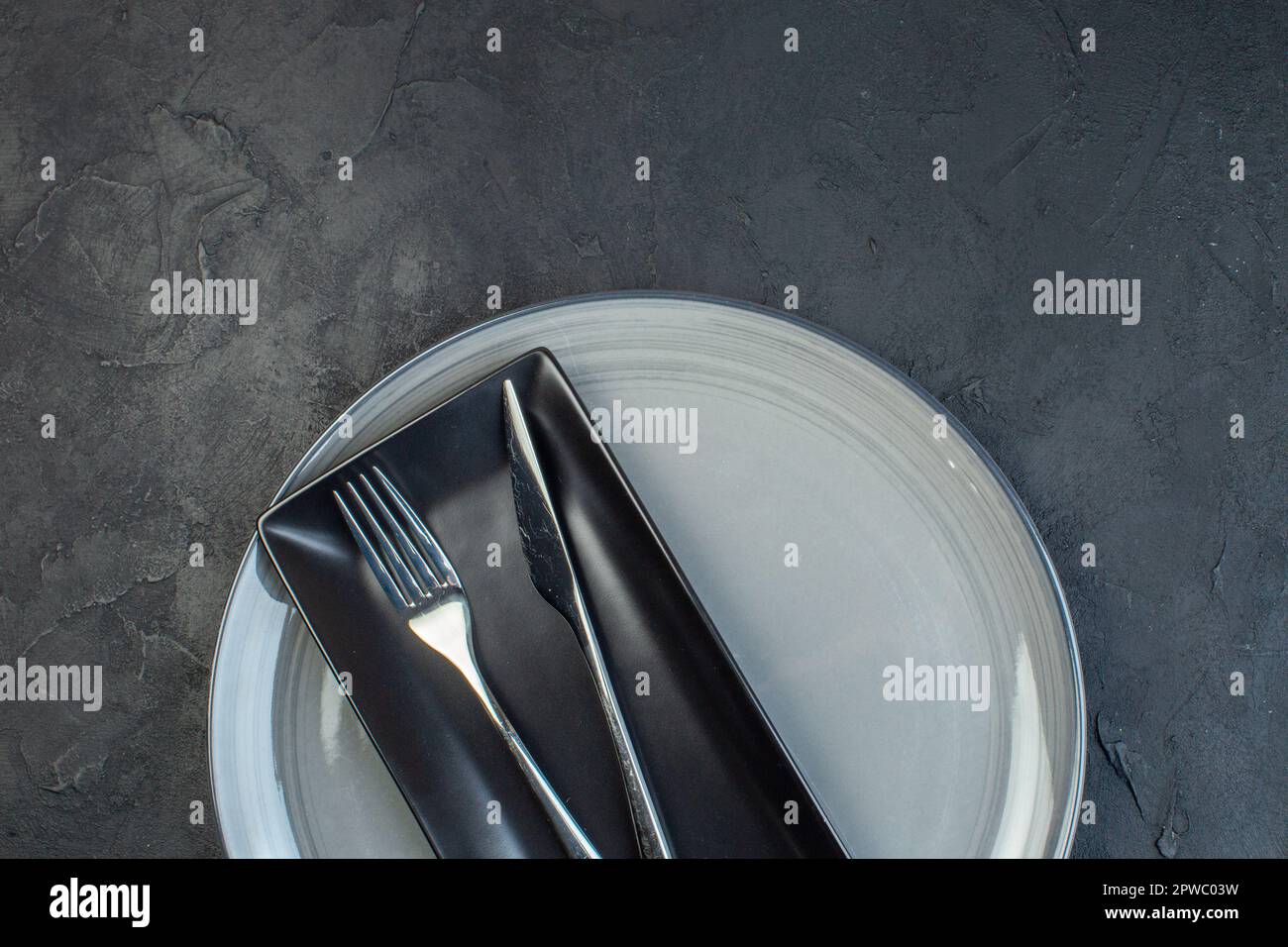 top view long black plate with fork and knife in gray plate on dark ...