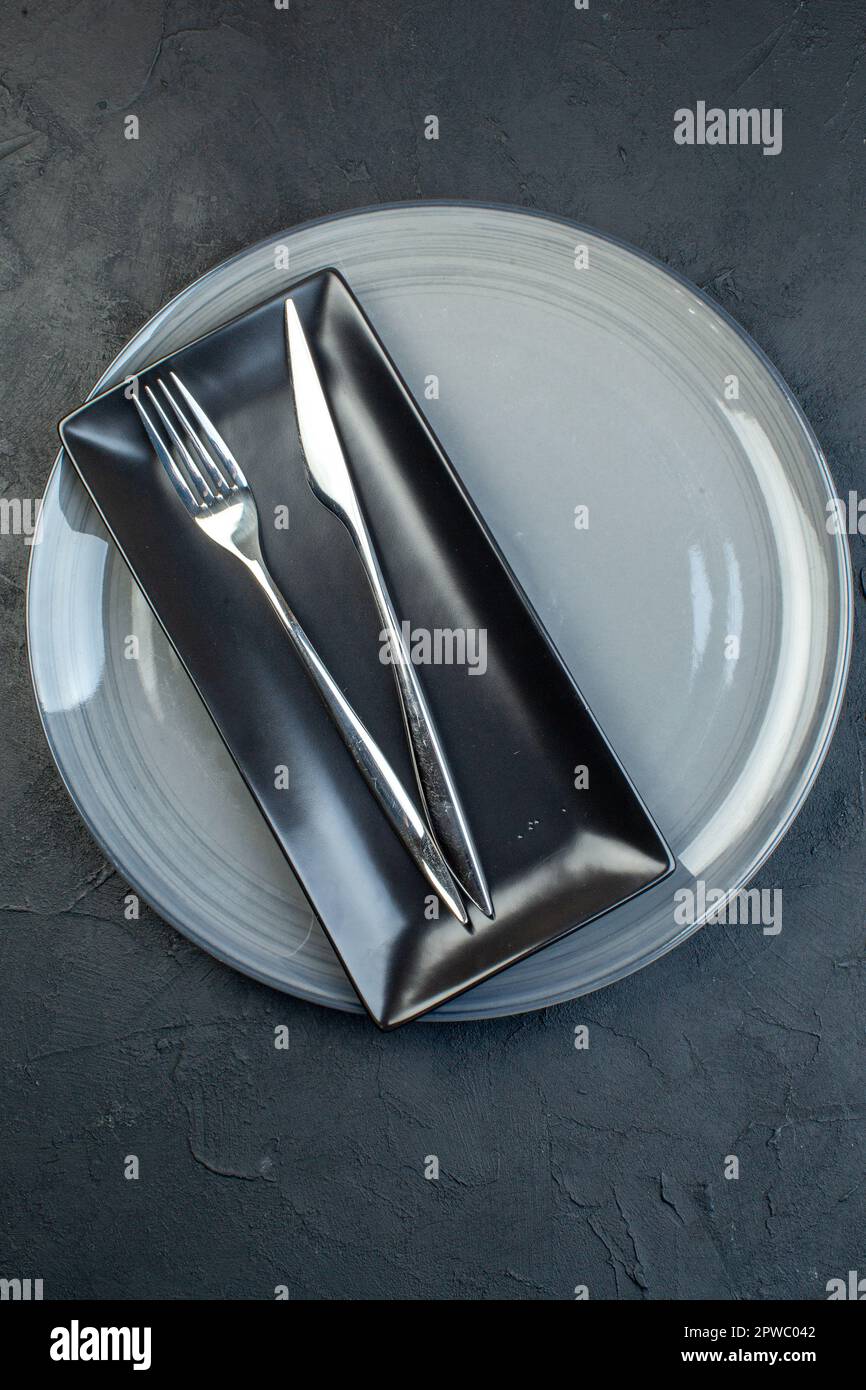 top view long black plate with fork and knife in gray plate on dark ...