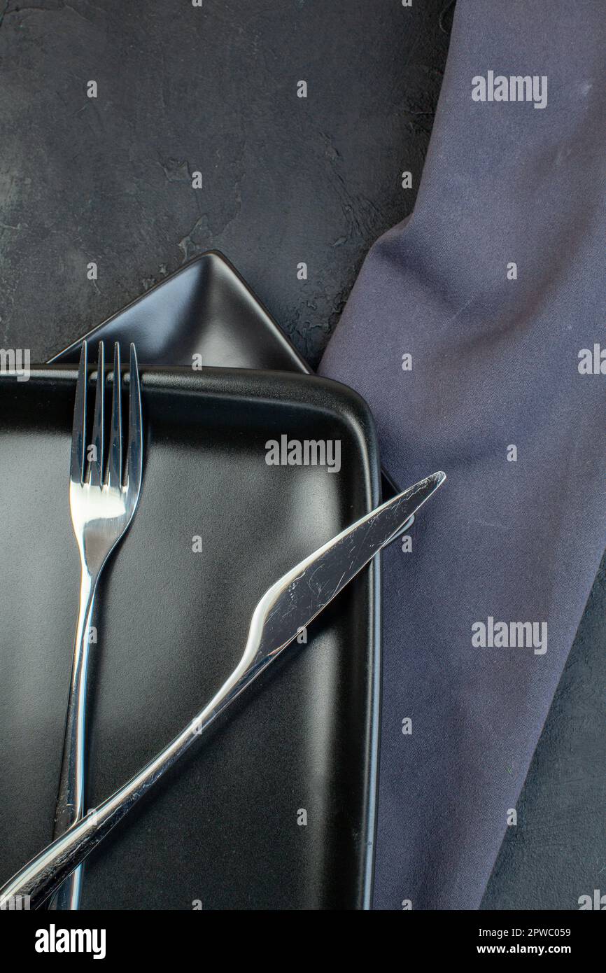 top view long black plate with fork and knife inside on dark background ...