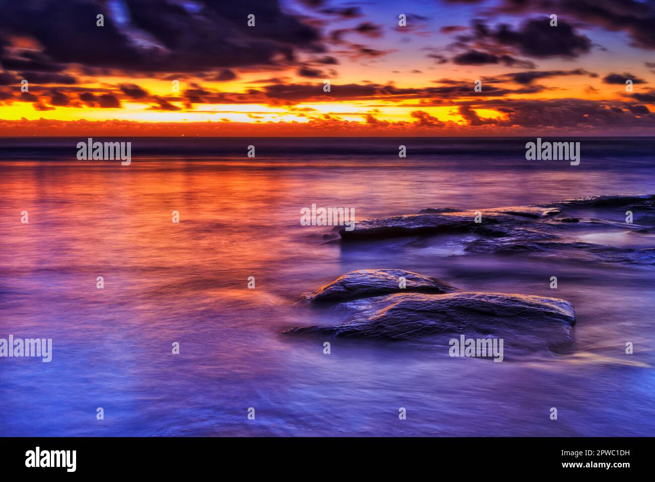 Warm sunlight sunrise over Pacific ocean horizon off Caves beach on ...