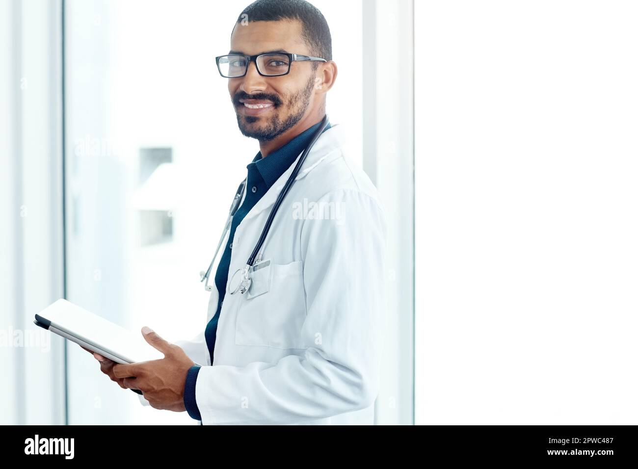 I read my medical journals in digital form. Portrait of a young doctor ...