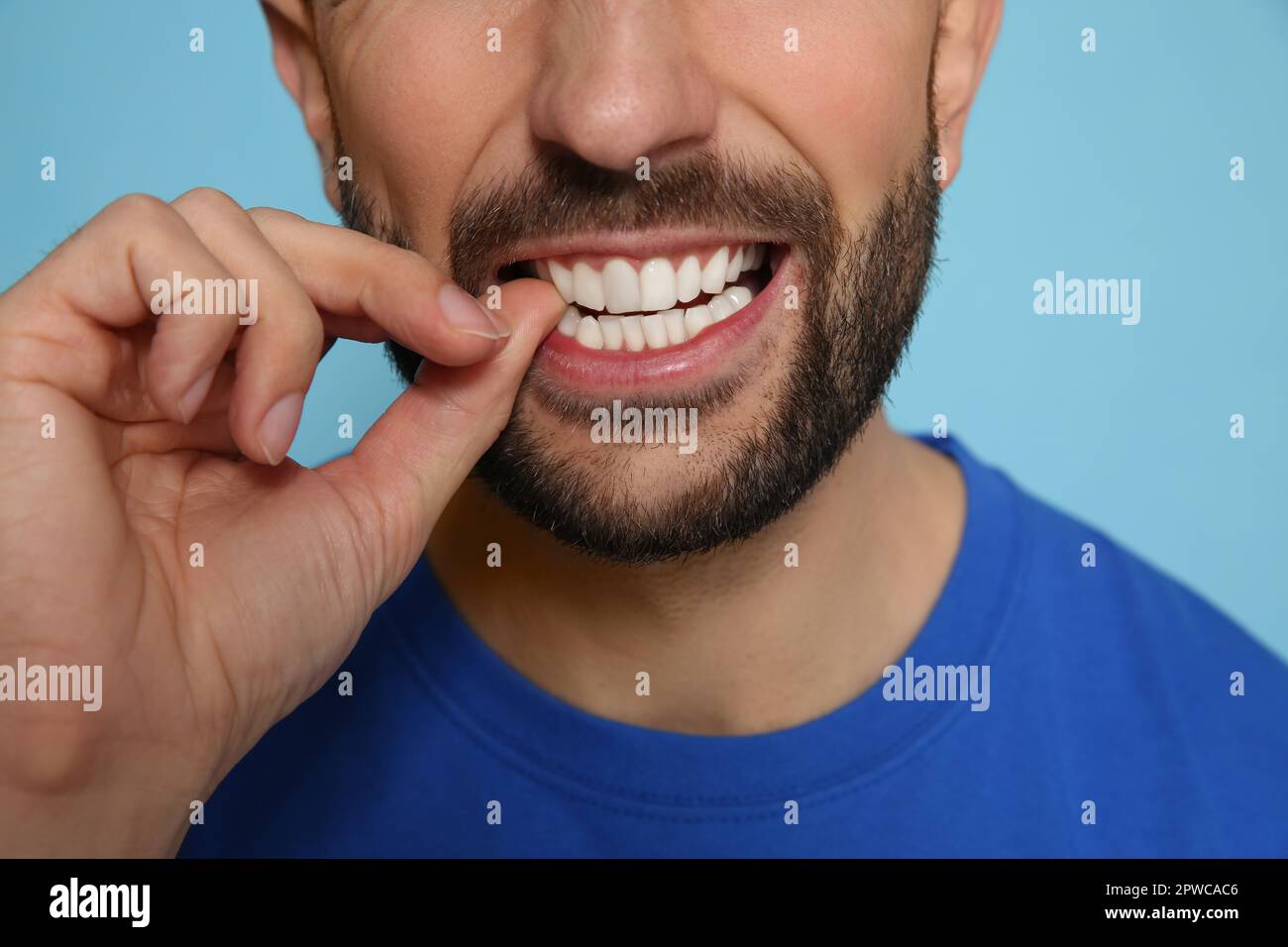 Man biting his nails on light blue background, closeup Stock Photo - Alamy