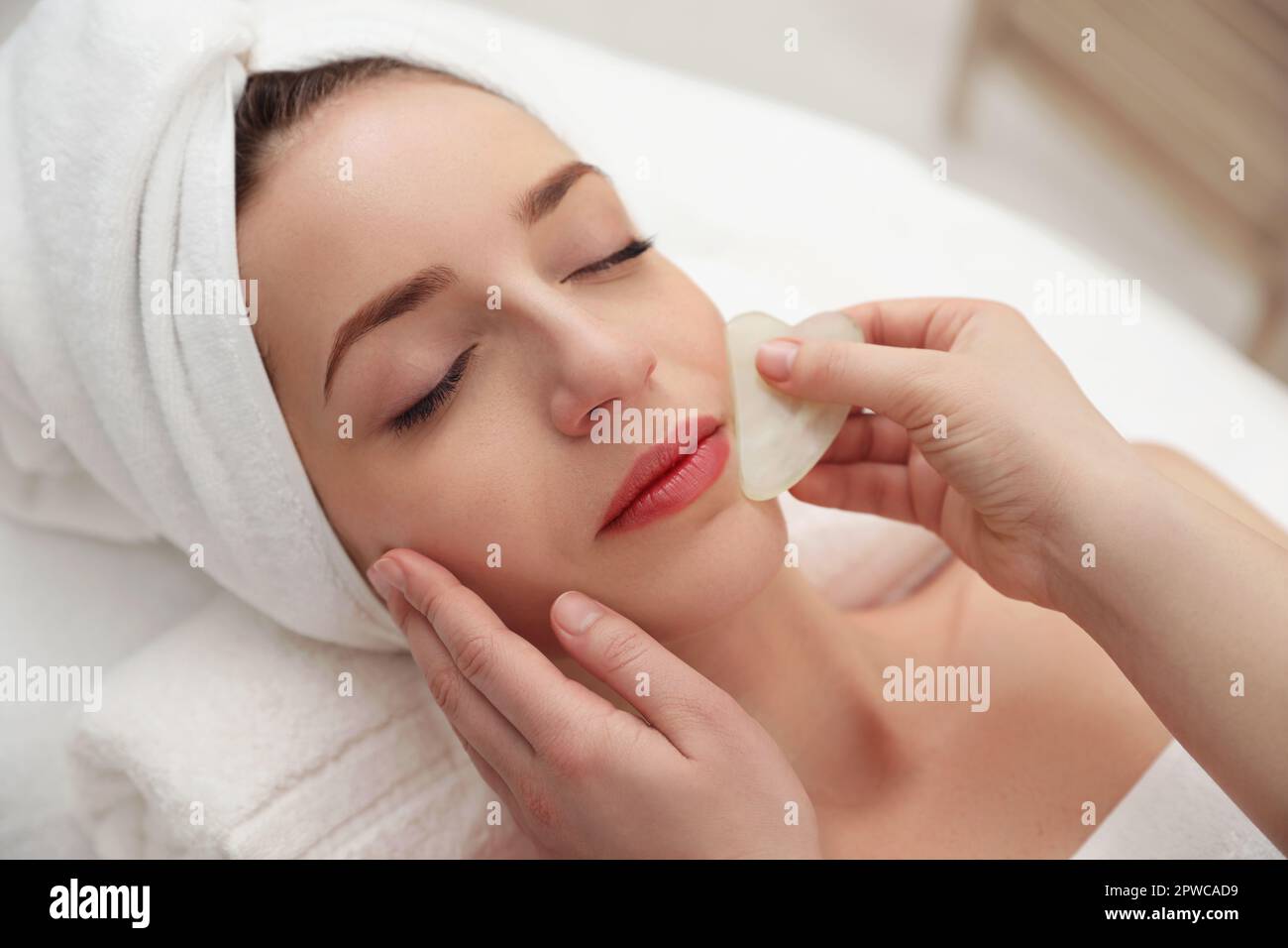 Young woman receiving facial massage with gua sha tool in beauty salon Stock Photo - Alamy