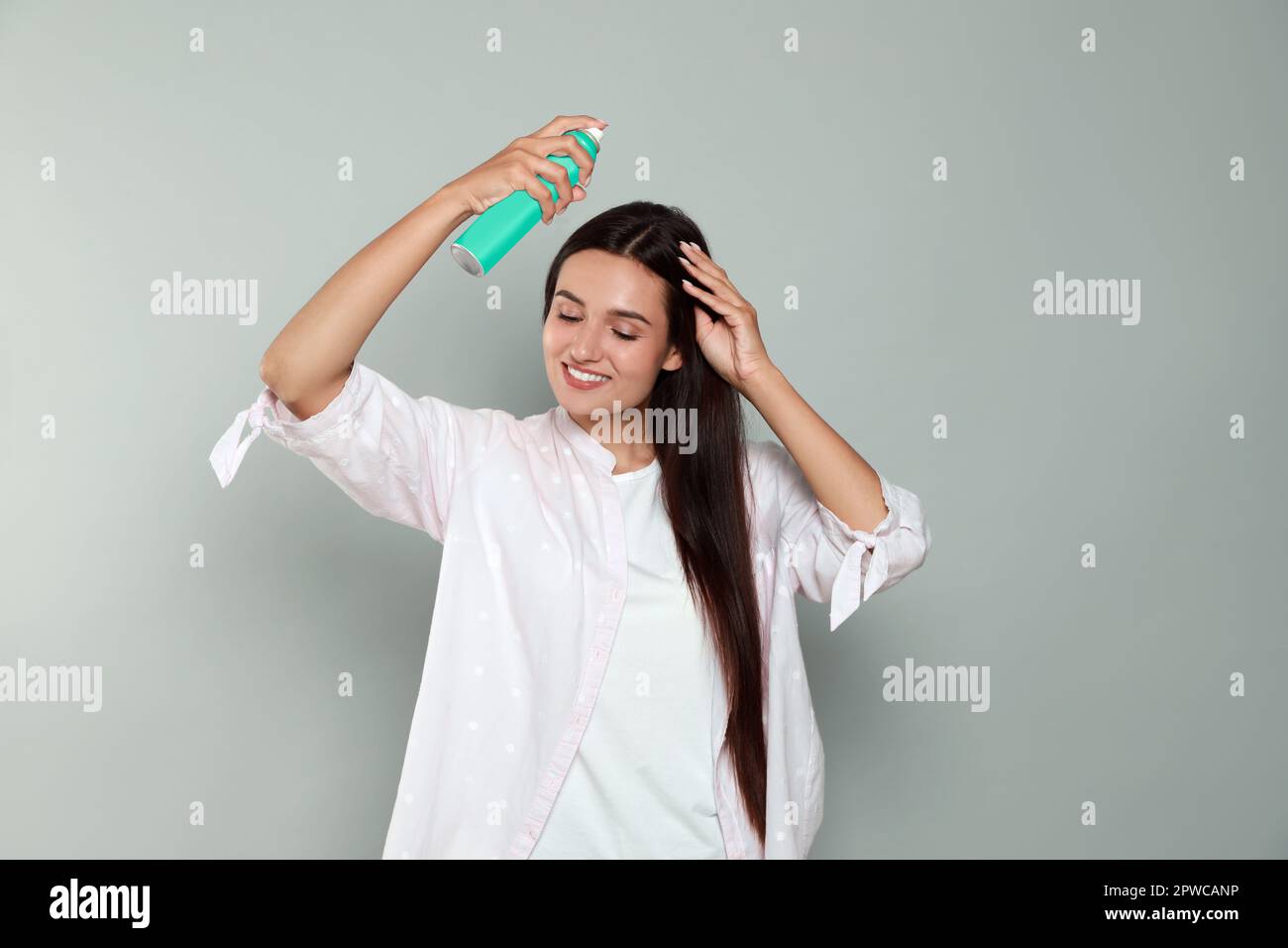 Woman applying dry shampoo onto her hair on light grey background Stock ...