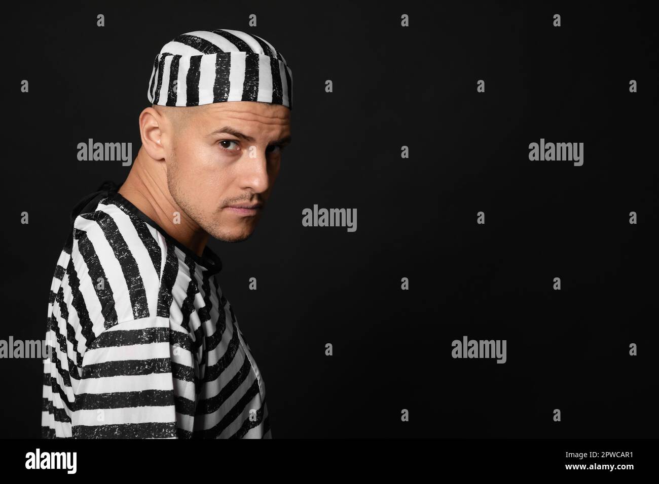 Prisoner in striped uniform on black background, space for text Stock ...