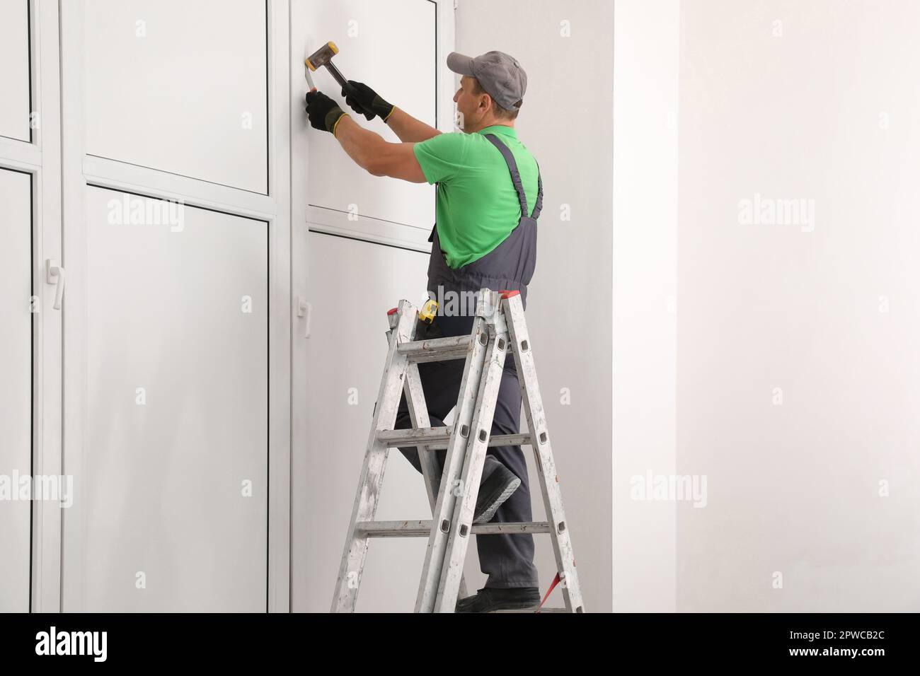Worker on folding ladder installing window indoors Stock Photo - Alamy