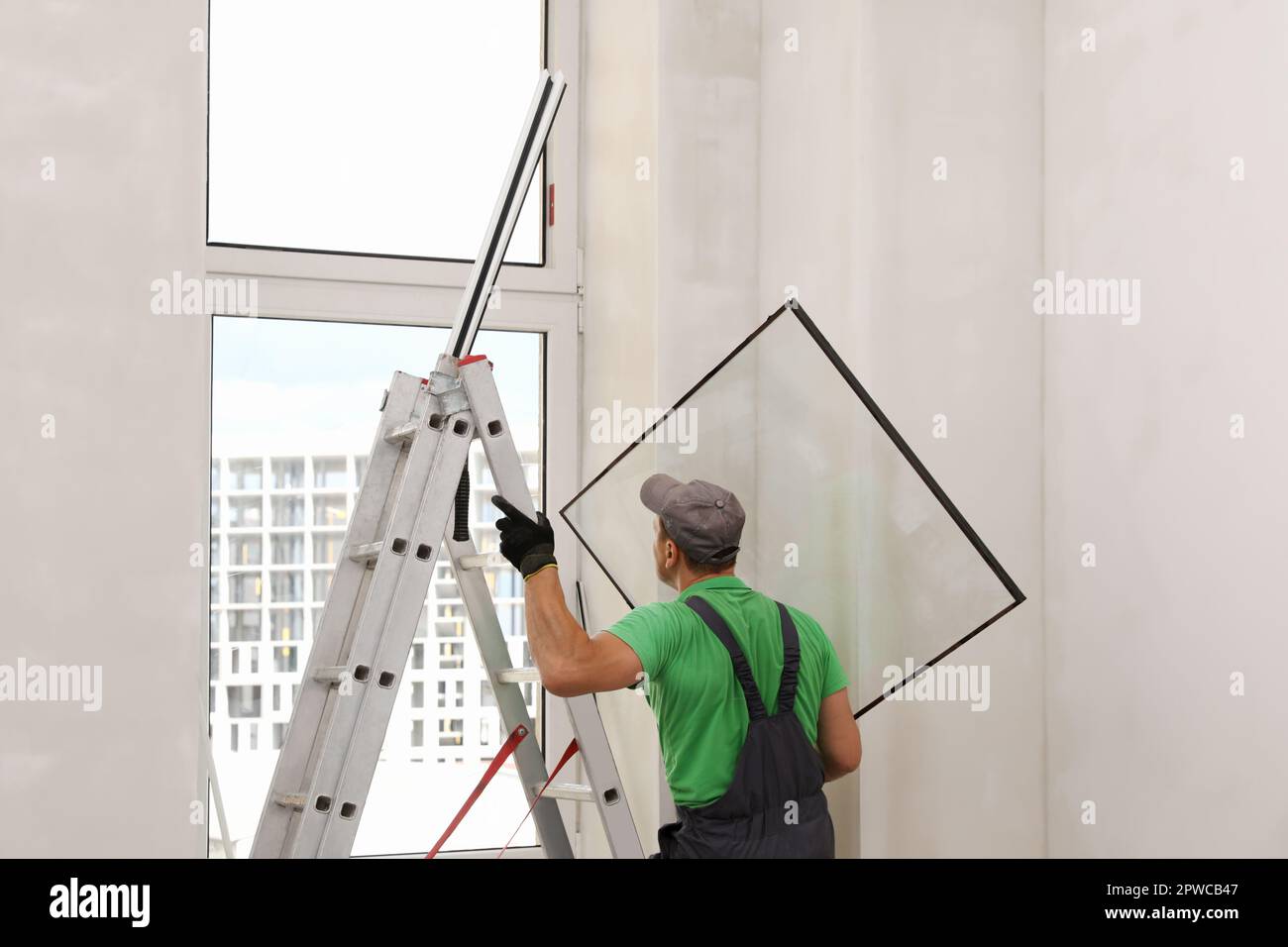 Worker in uniform holding double glazing window indoors, back view ...