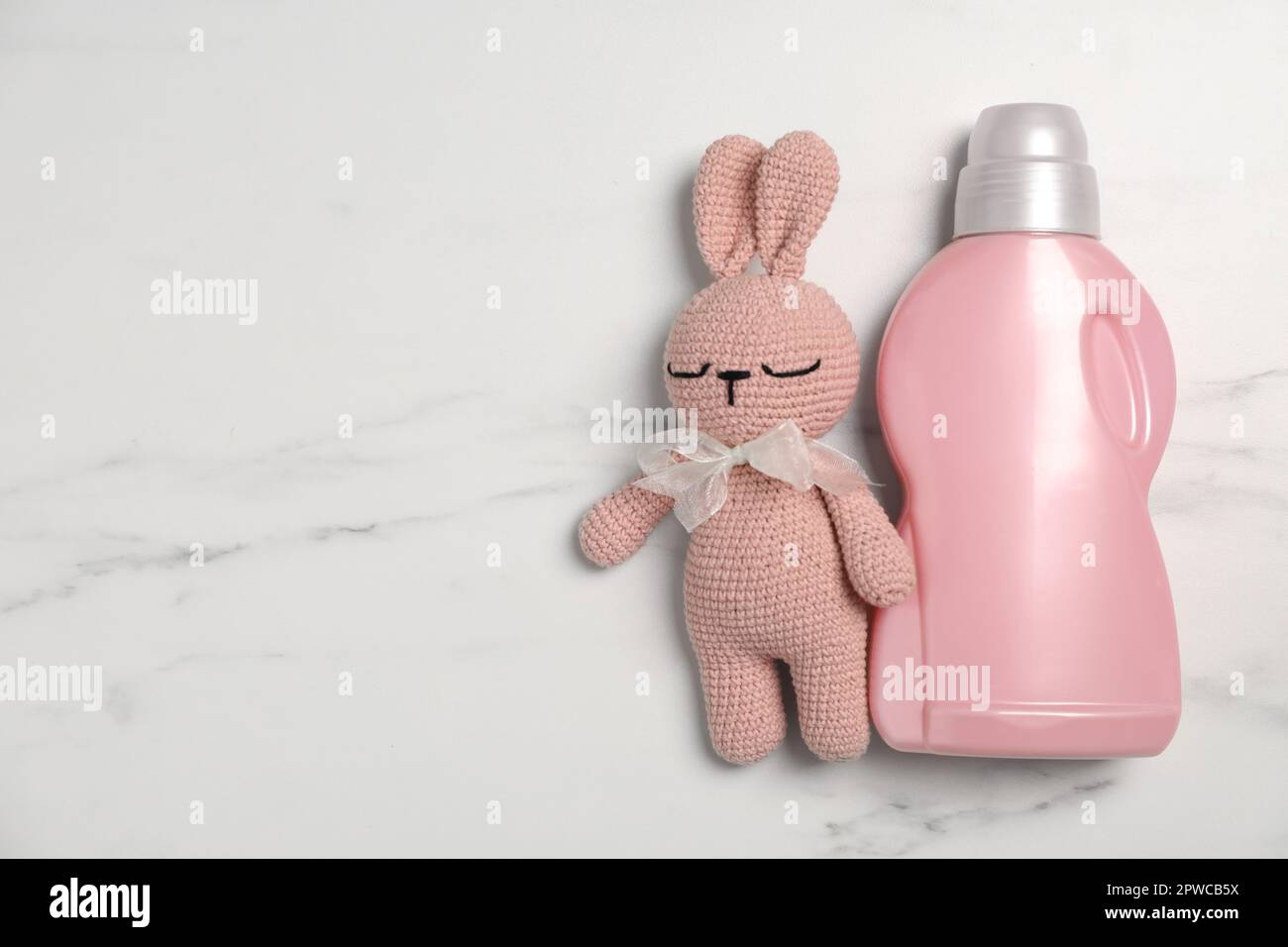 Bottle of laundry detergent and rabbit toy on white marble table, flat ...