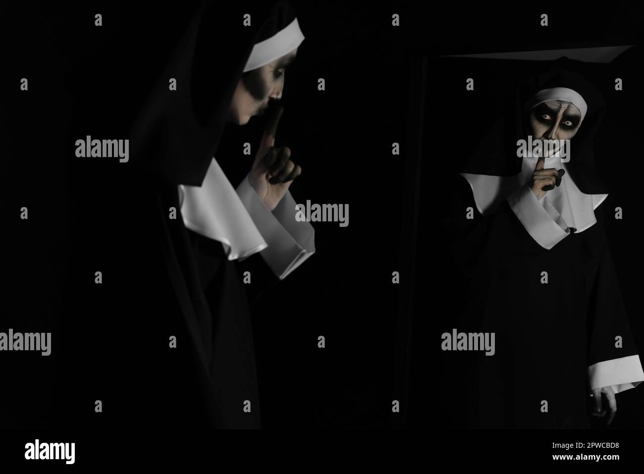 Scary devilish nun near mirror on black background. Halloween party ...