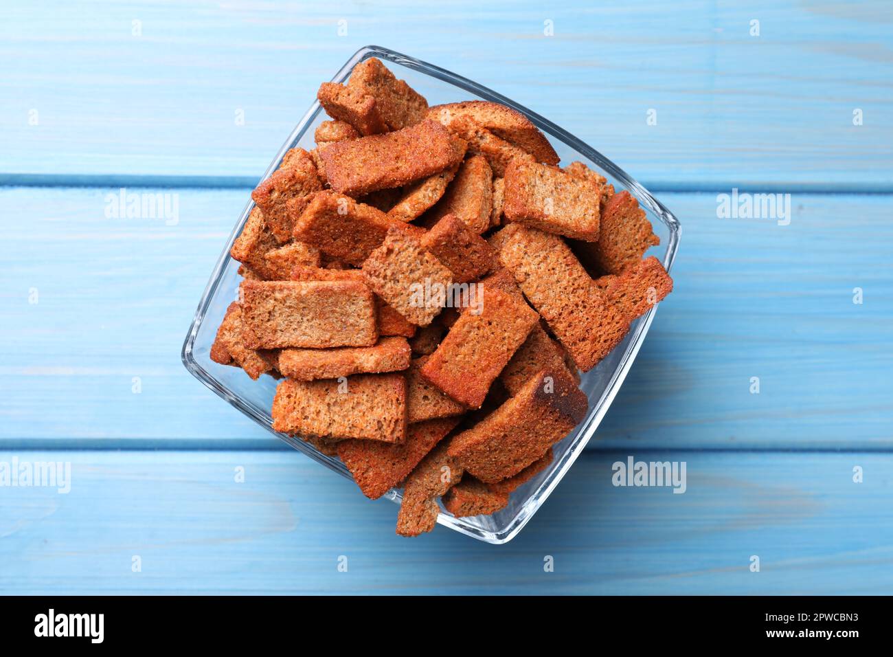 Crispy rye rusks in bowl on light blue wooden table, top view Stock ...