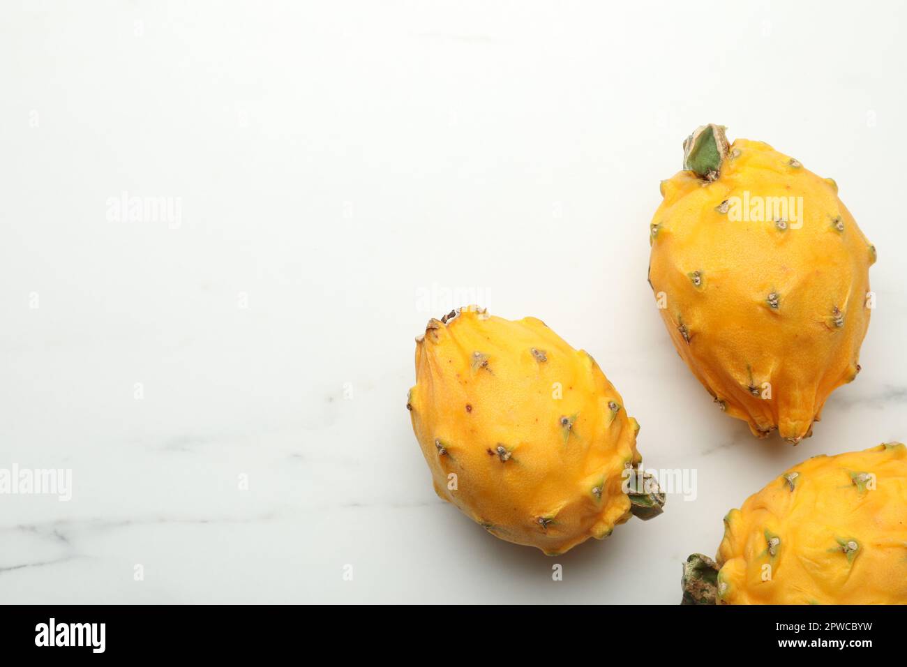 Delicious yellow pitahaya fruits on white marble table, flat lay. Space ...