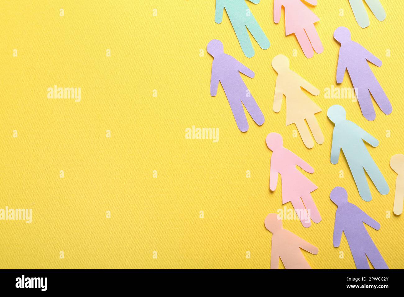Many different paper human figures on yellow background, flat lay with ...