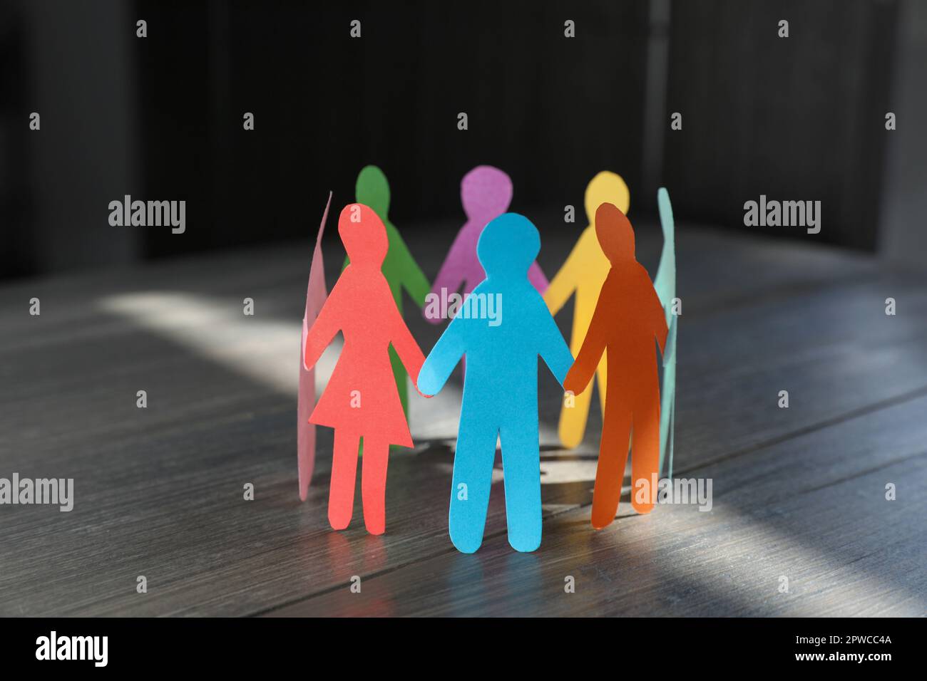 Paper human figures making circle on wooden table. Diversity and ...